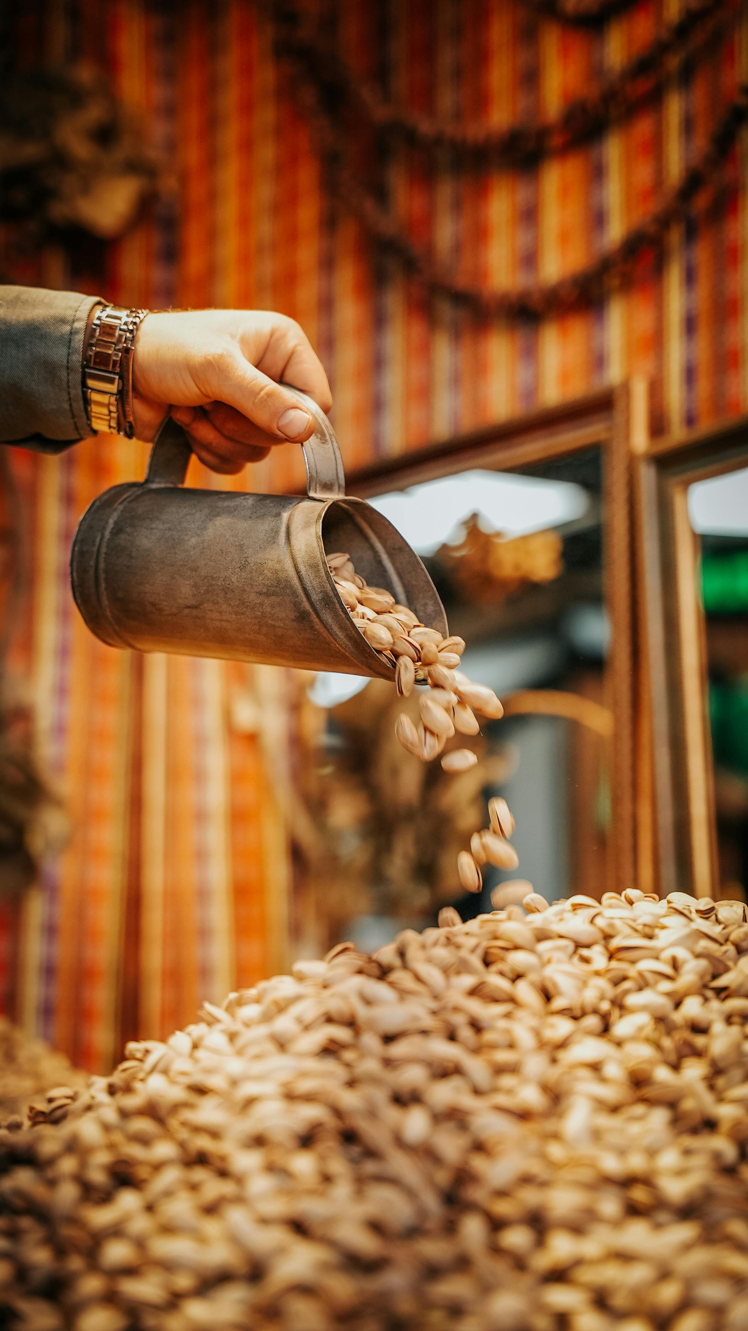 Hand Pouring Pistachio Nuts on a Heap · Free Stock Photo