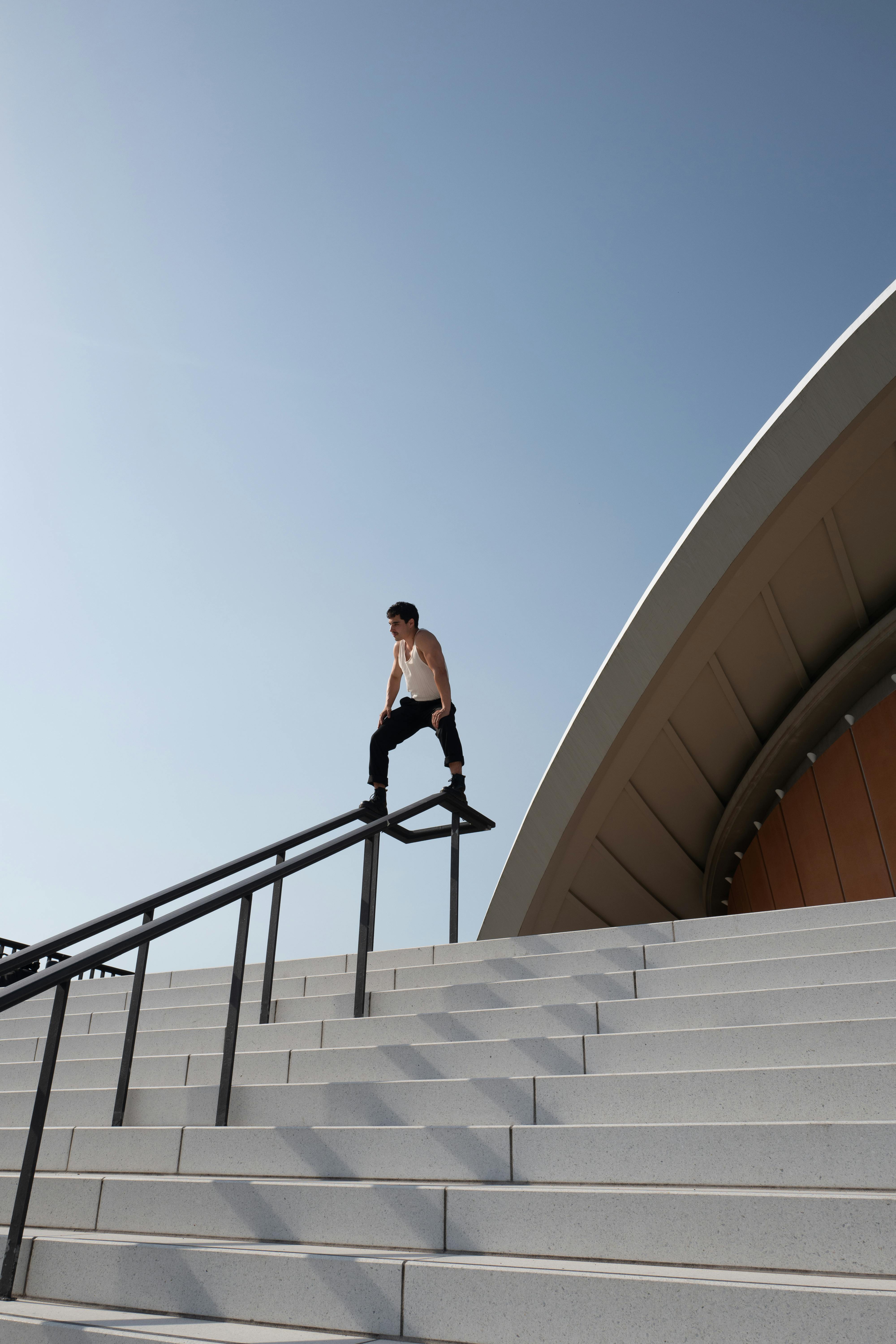 Man Standing on Handrails Bars on Stairs · Free Stock Photo