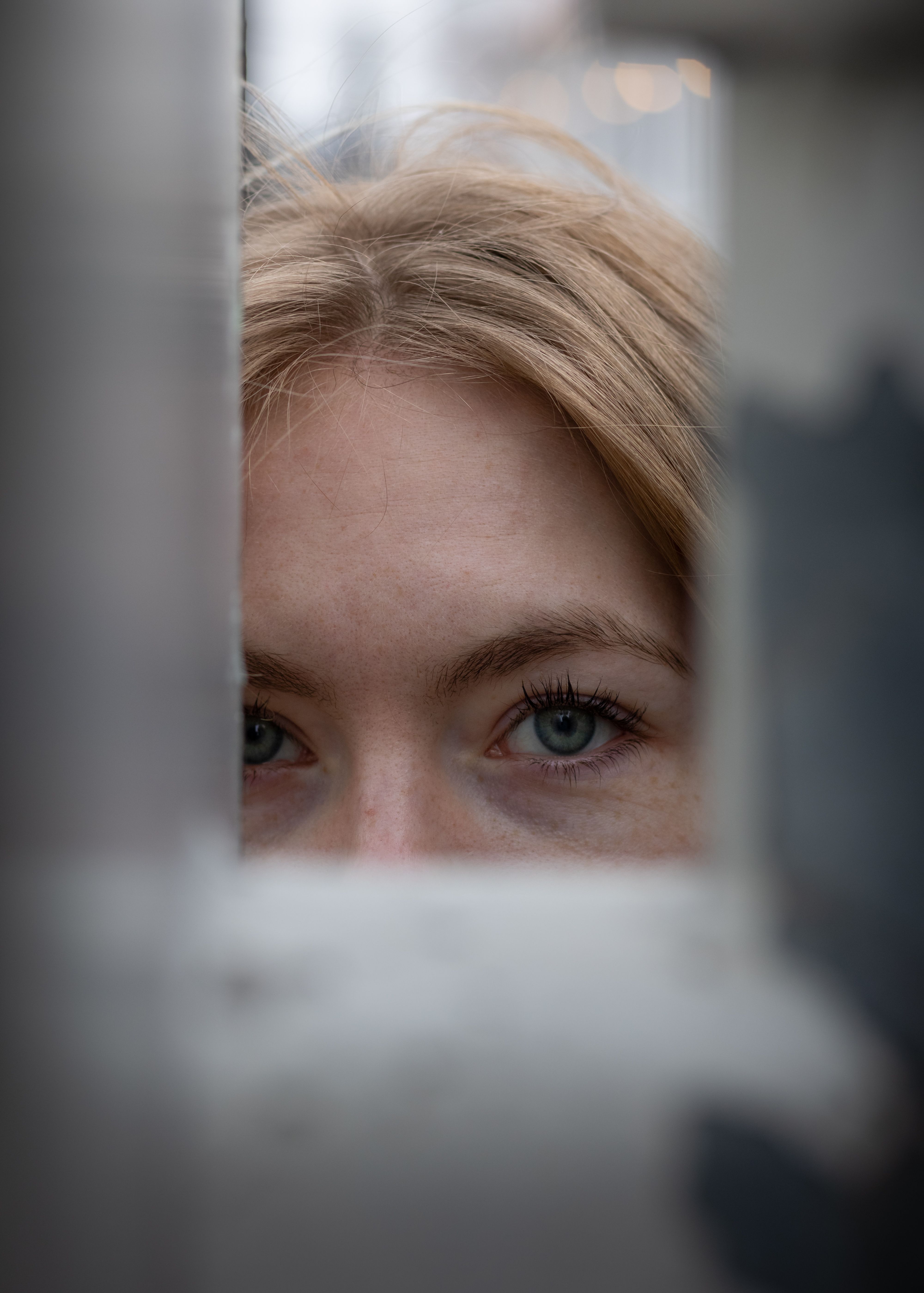 A woman peeking through a fence with her eyes open · Free Stock Photo