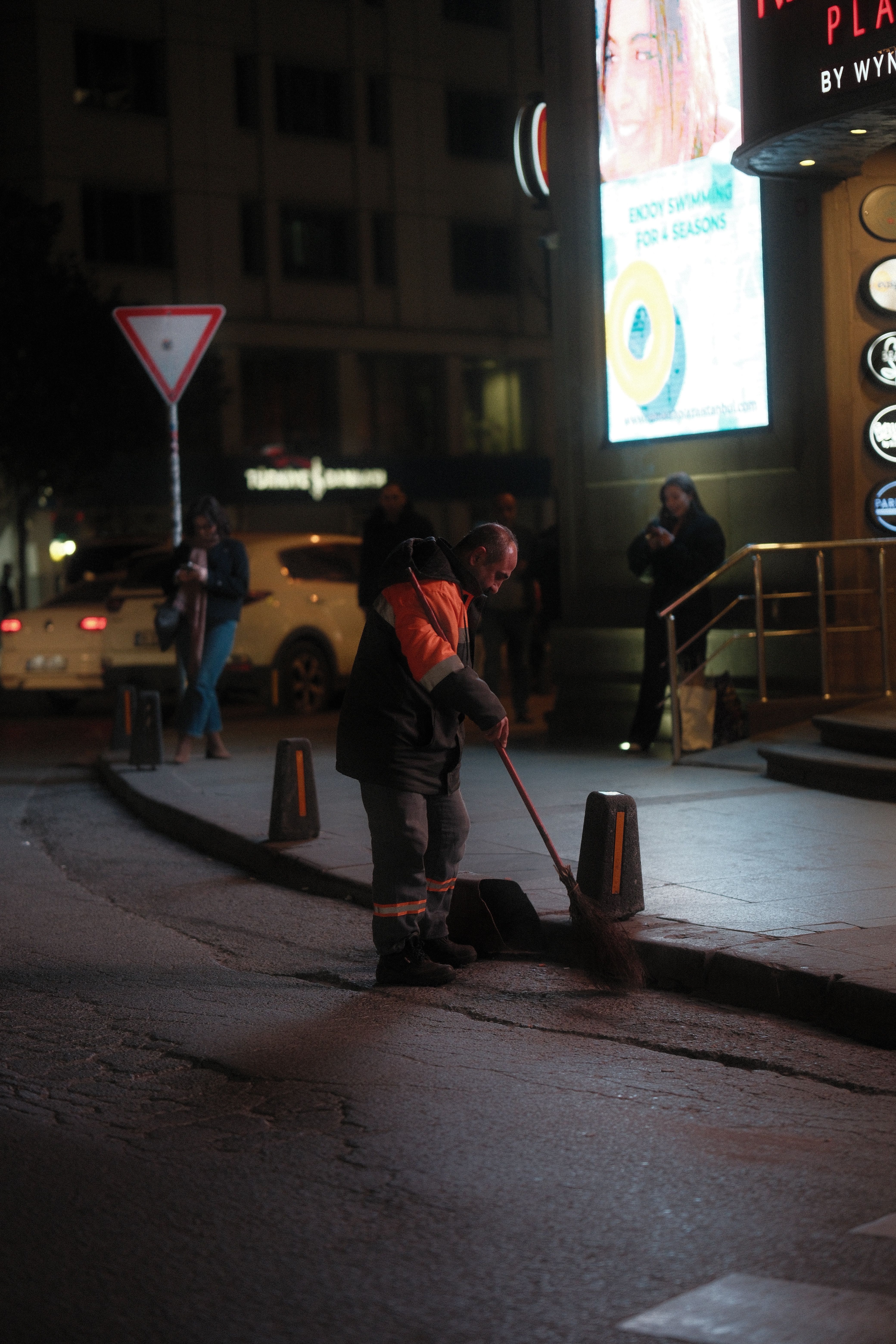 A Man Cleaning the Street in a City in the Evening · Free Stock Photo