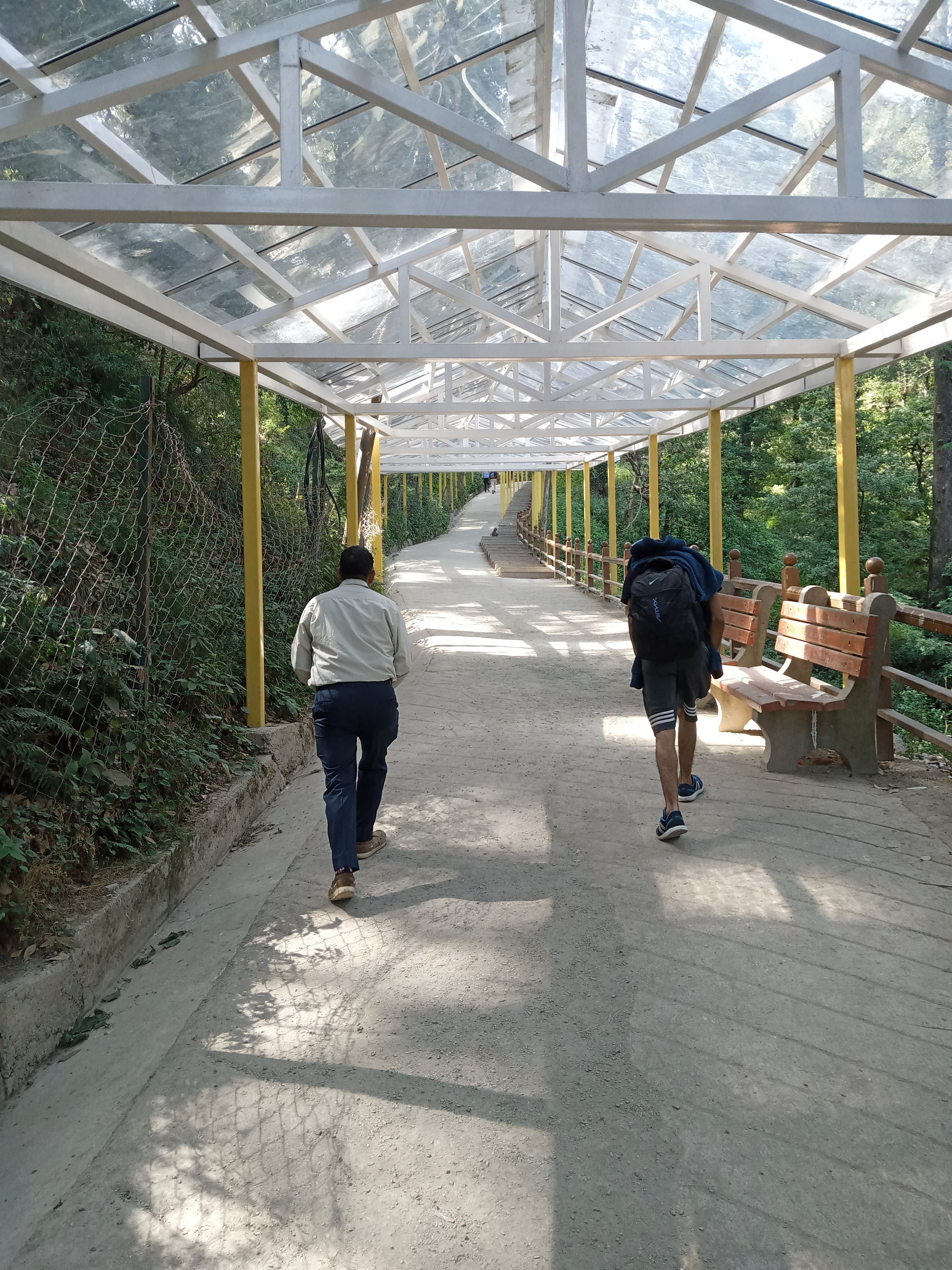 Two people walking under a covered walkway · Free Stock Photo