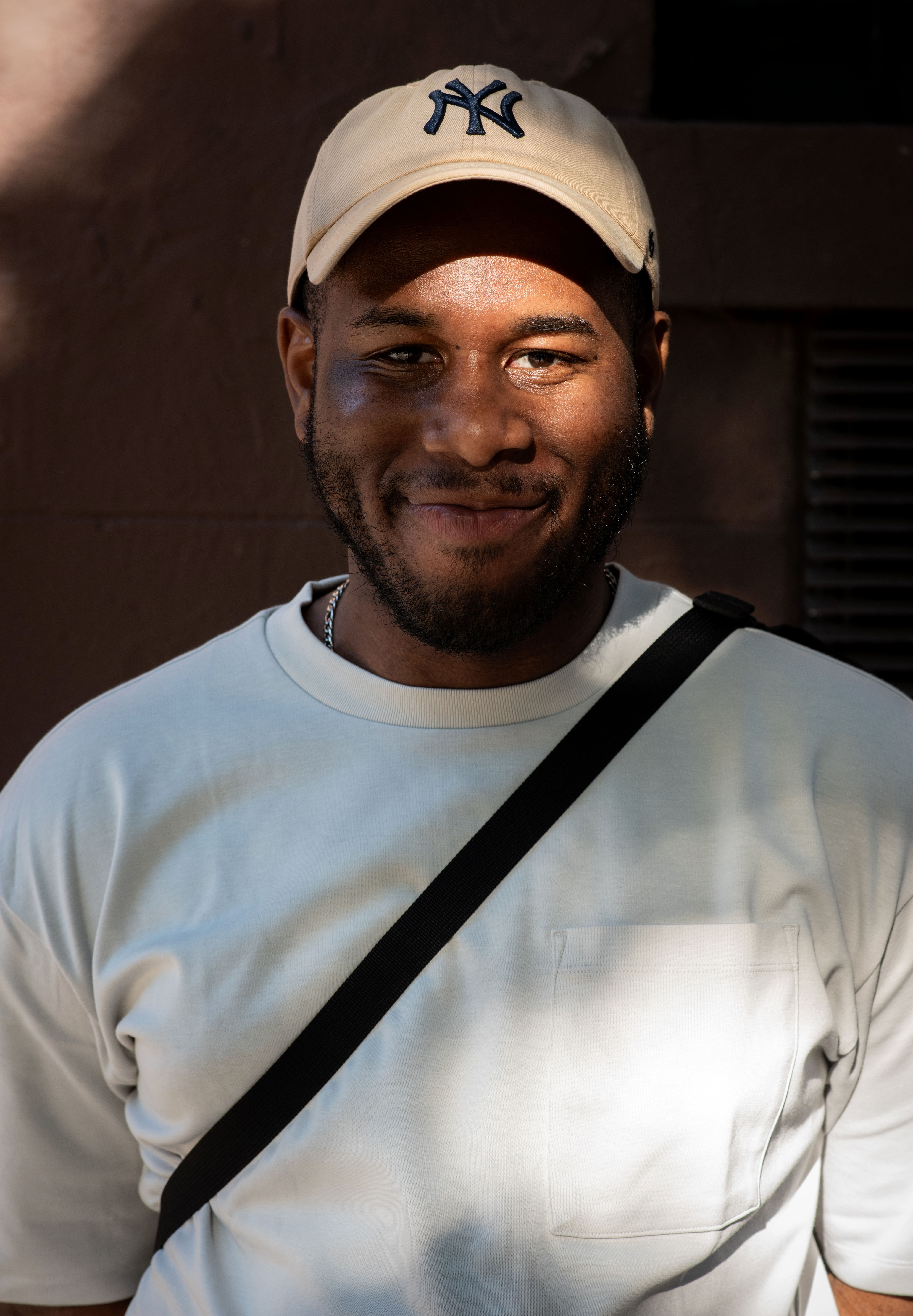 A smiling man in a baseball cap and white shirt · Free Stock Photo