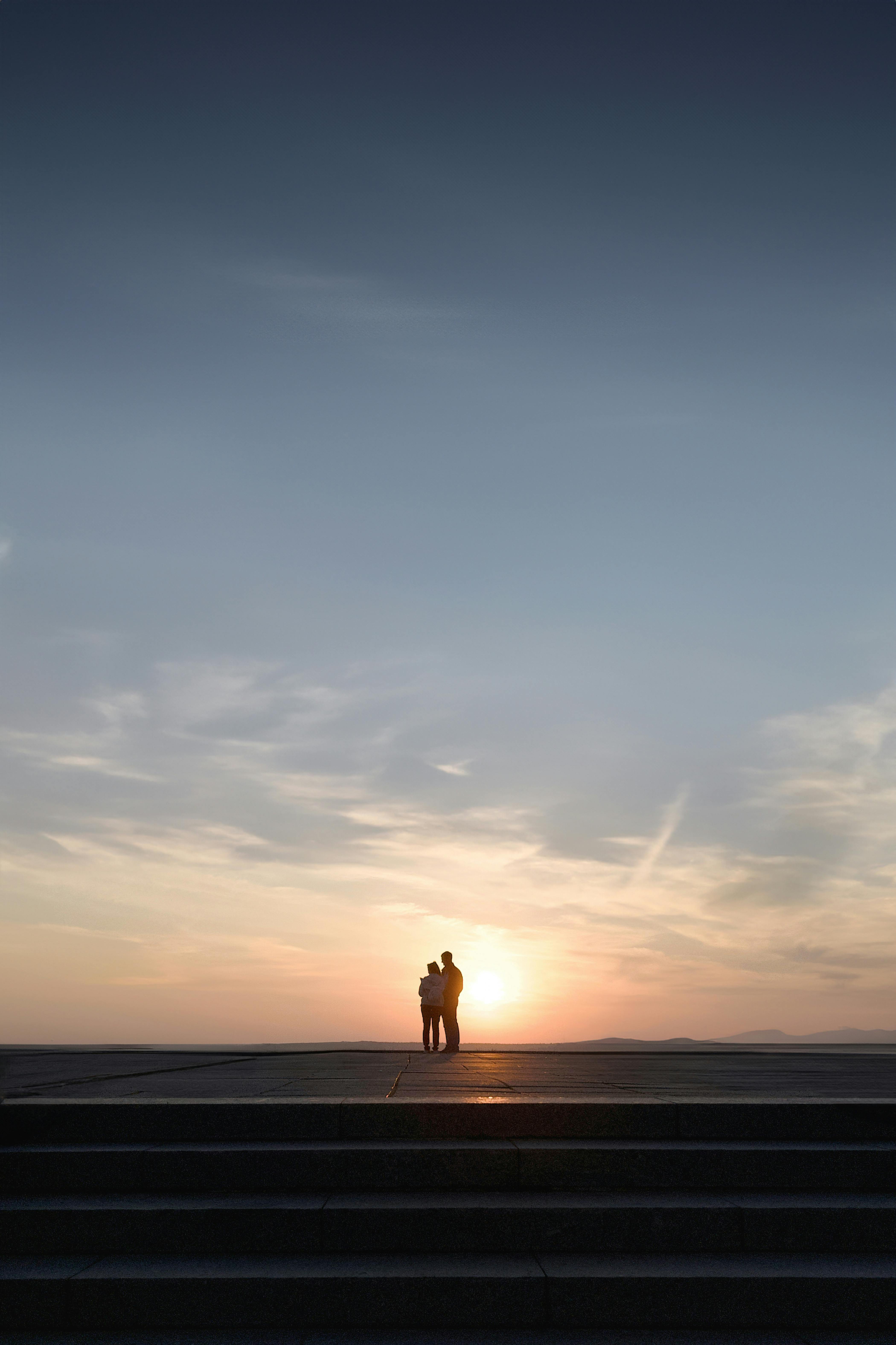 Couple Standing on Pavement at Sunset · Free Stock Photo