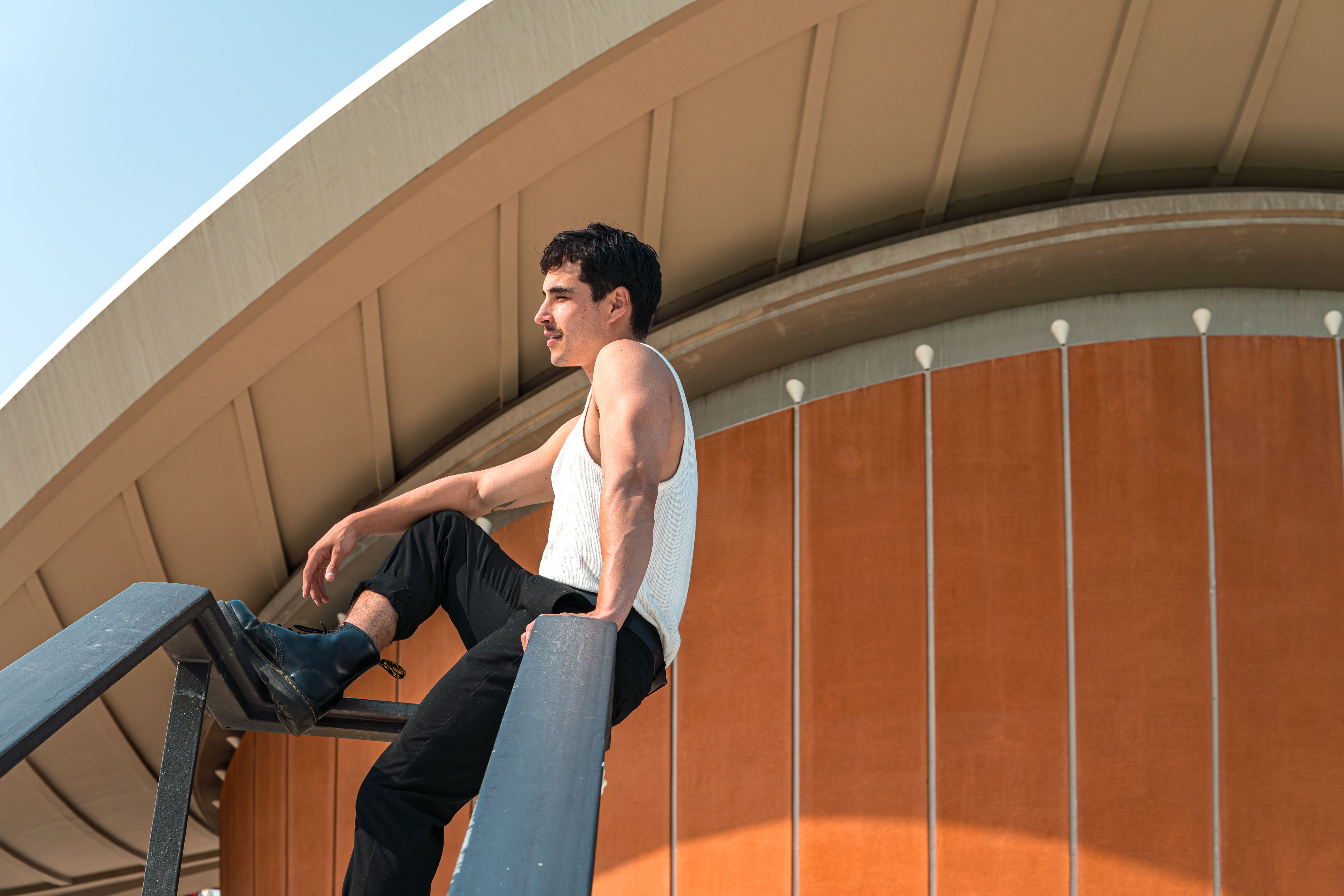 Brunette Man in Tank Top Sitting on Railing · Free Stock Photo