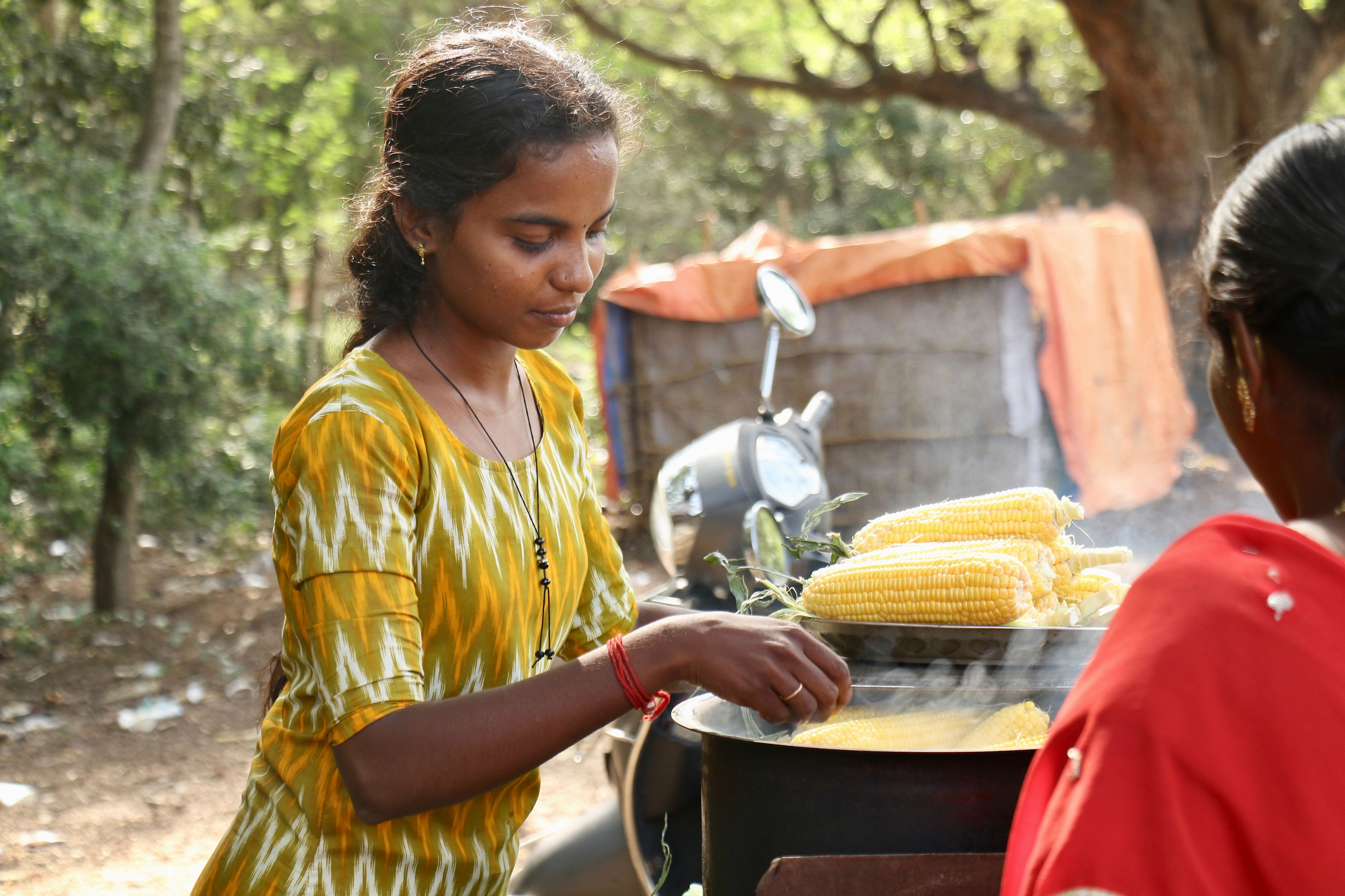 Young Woman Cooking Corn Cobs Outdoors · Free Stock Photo