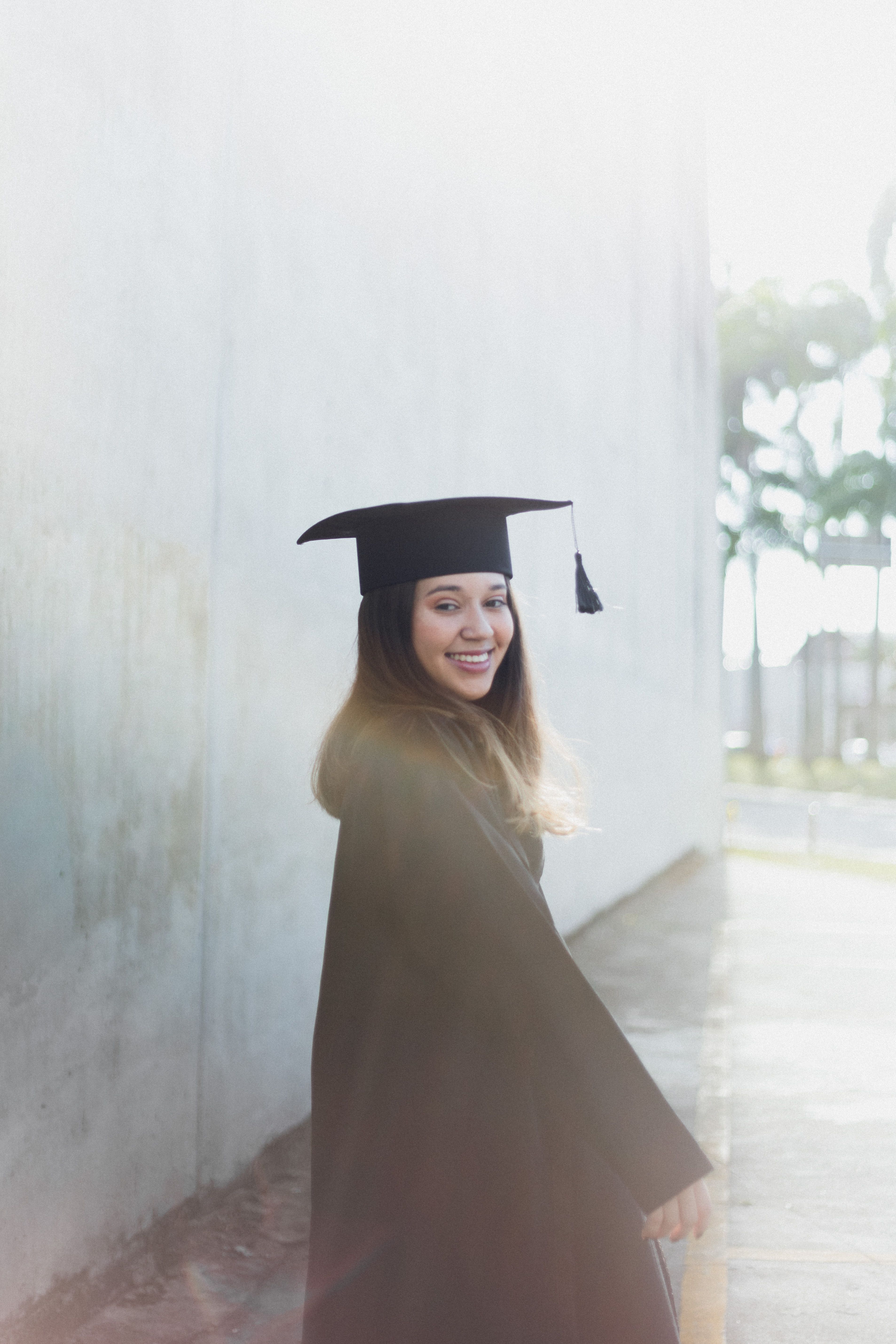 Woman Wearing Black Graduation Coat Sits on Stairs · Free Stock Photo