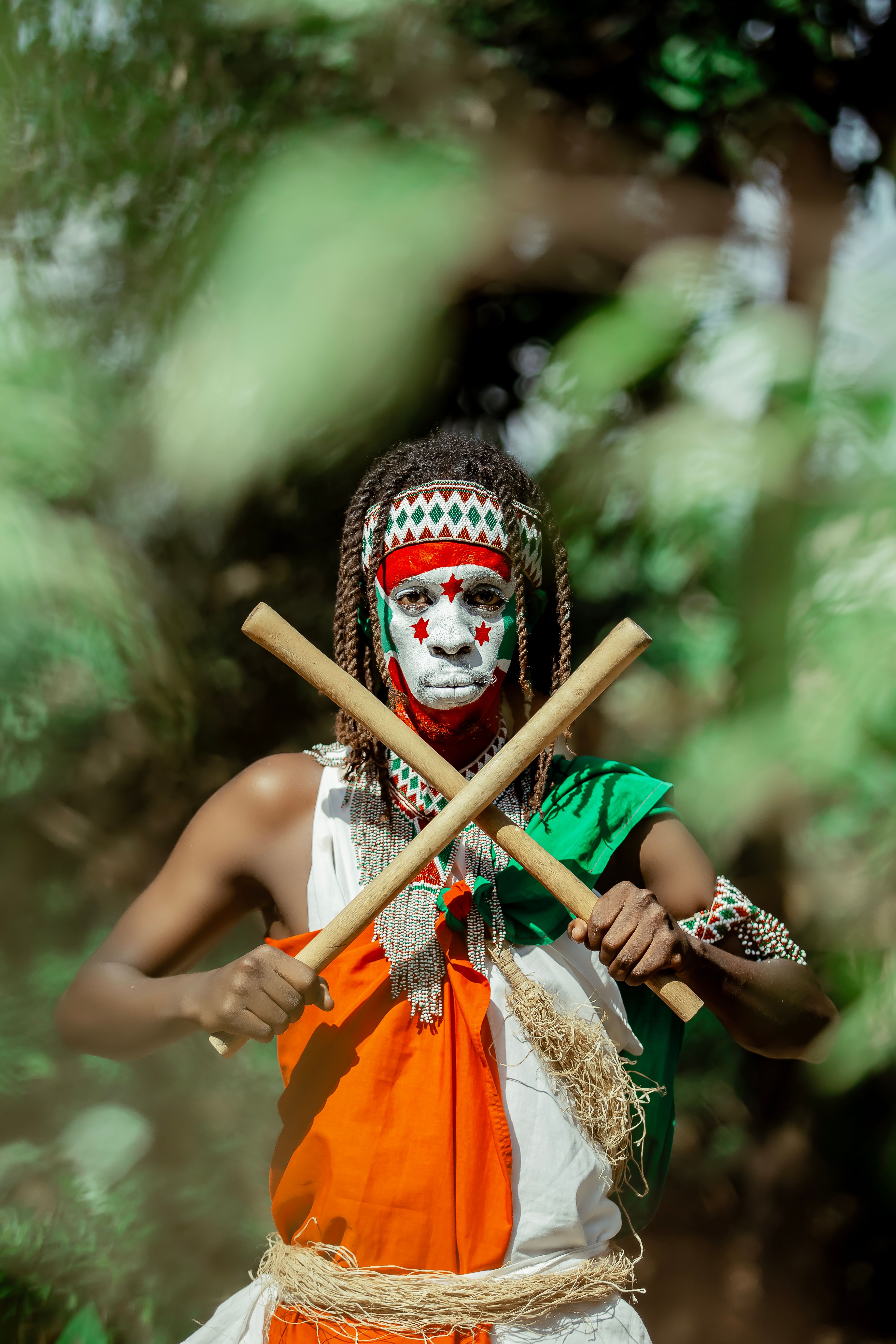 Man in Burundi Colors Holding Sticks Crossed · Free Stock Photo