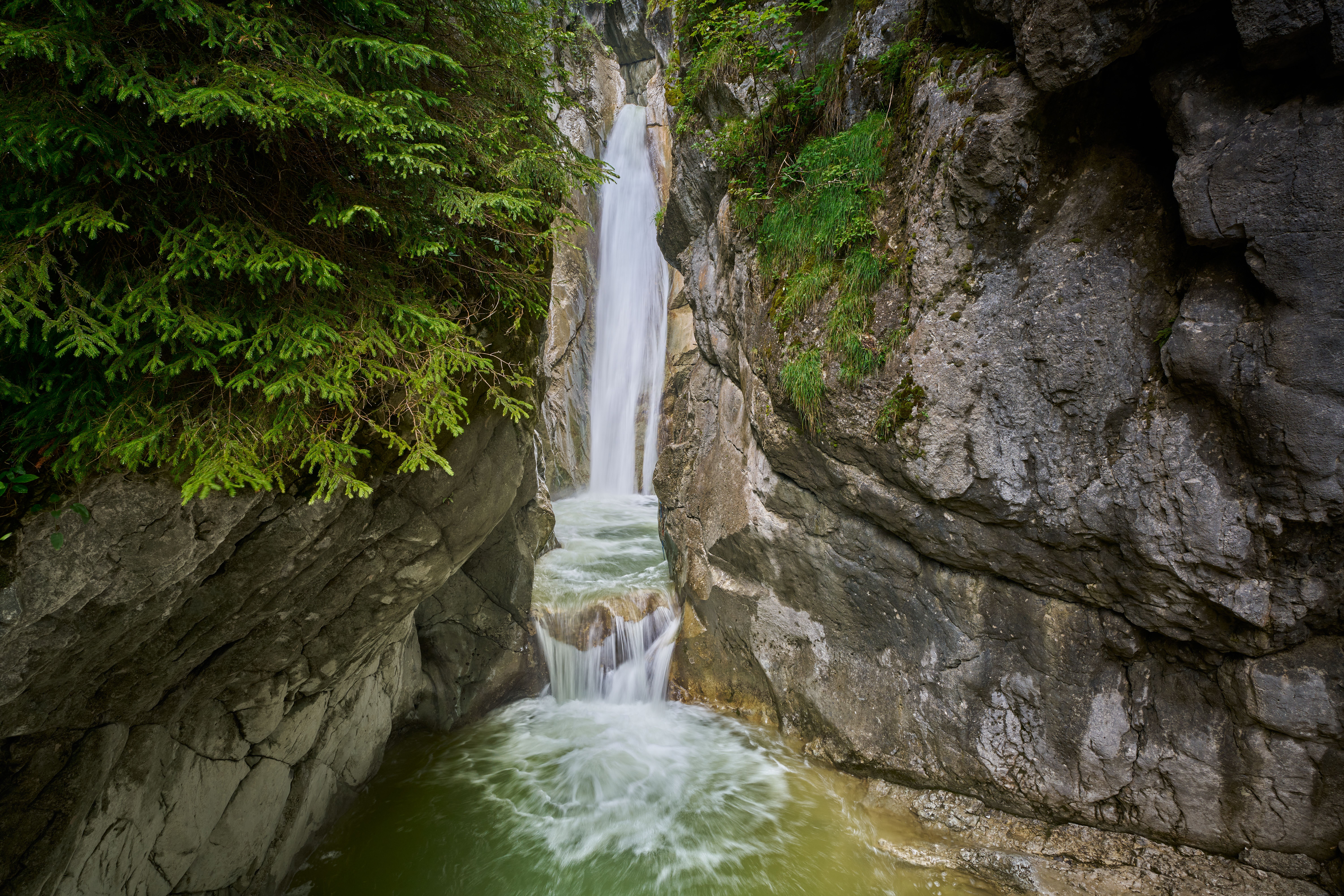 A waterfall is flowing through a narrow canyon · Free Stock Photo