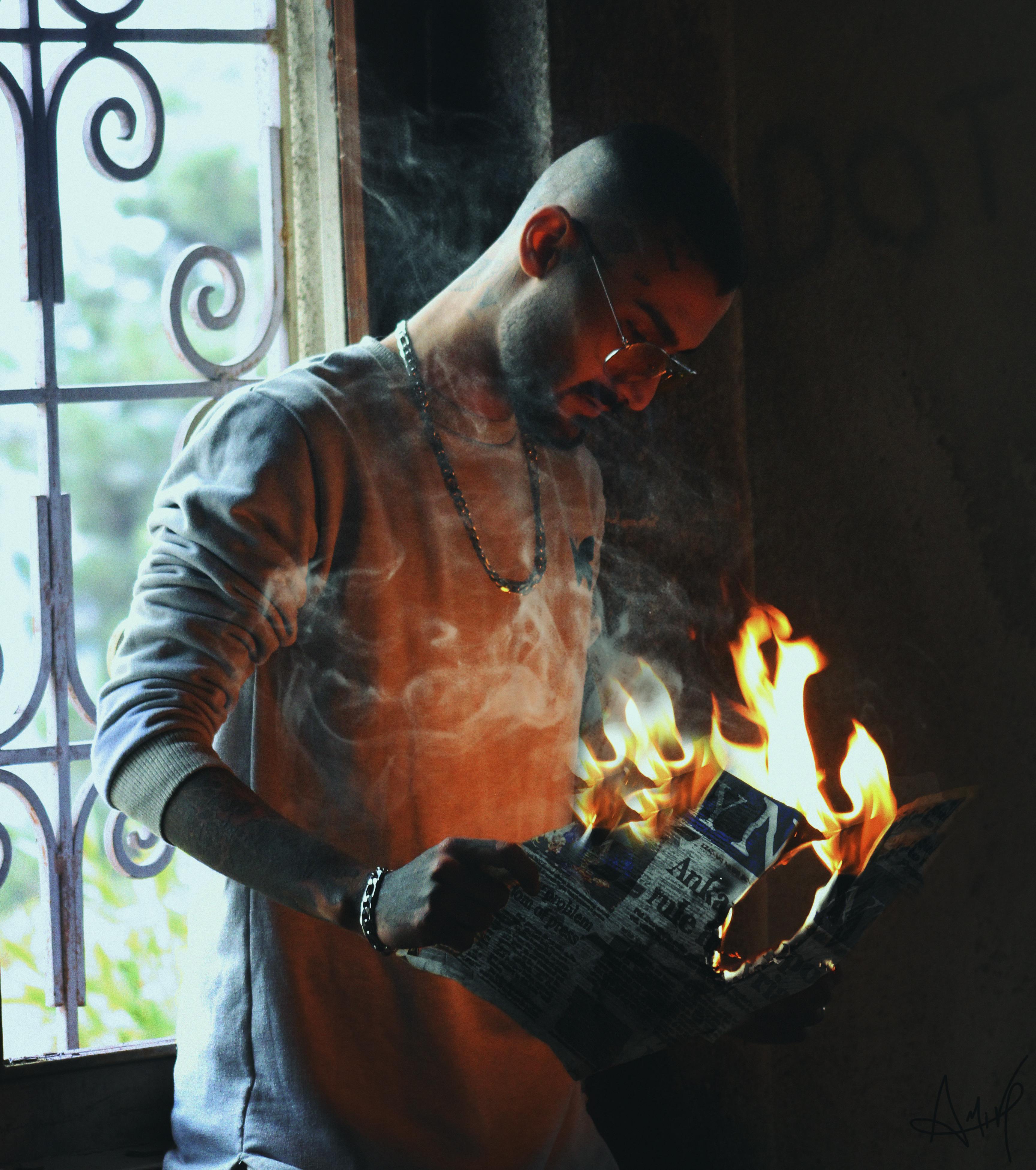 Man Holding Burning Paper by the Window · Free Stock Photo