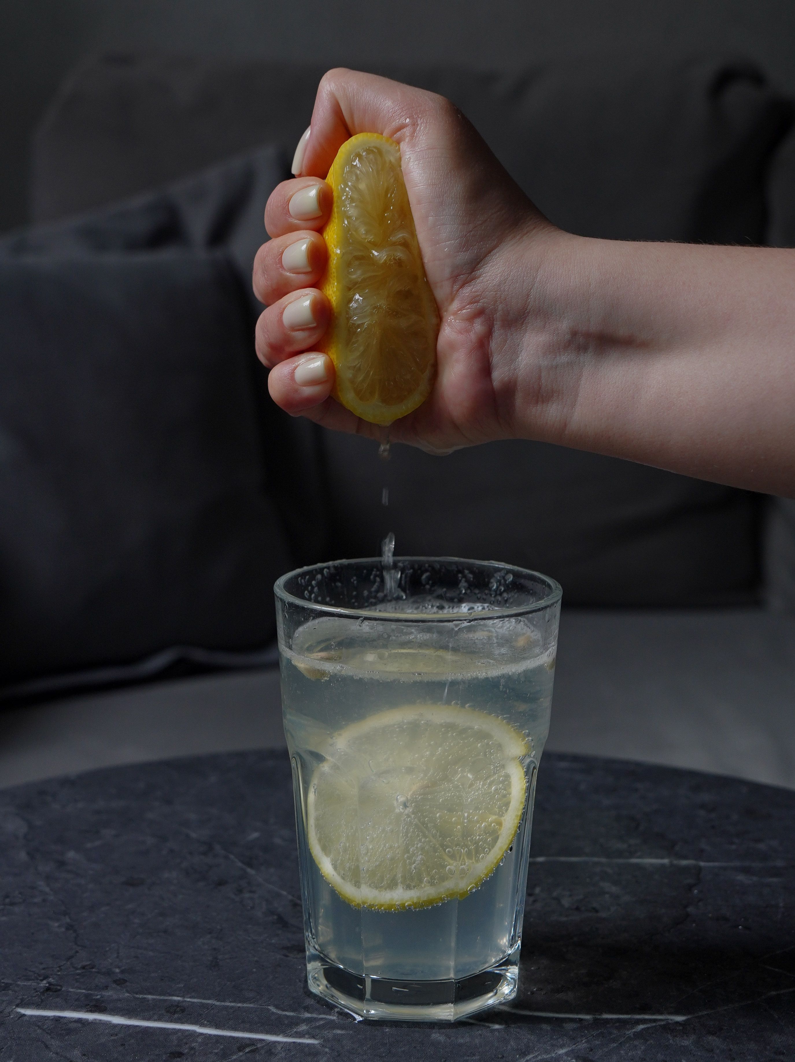 Hand Squeezing Lemon into Glass with Drink · Free Stock Photo