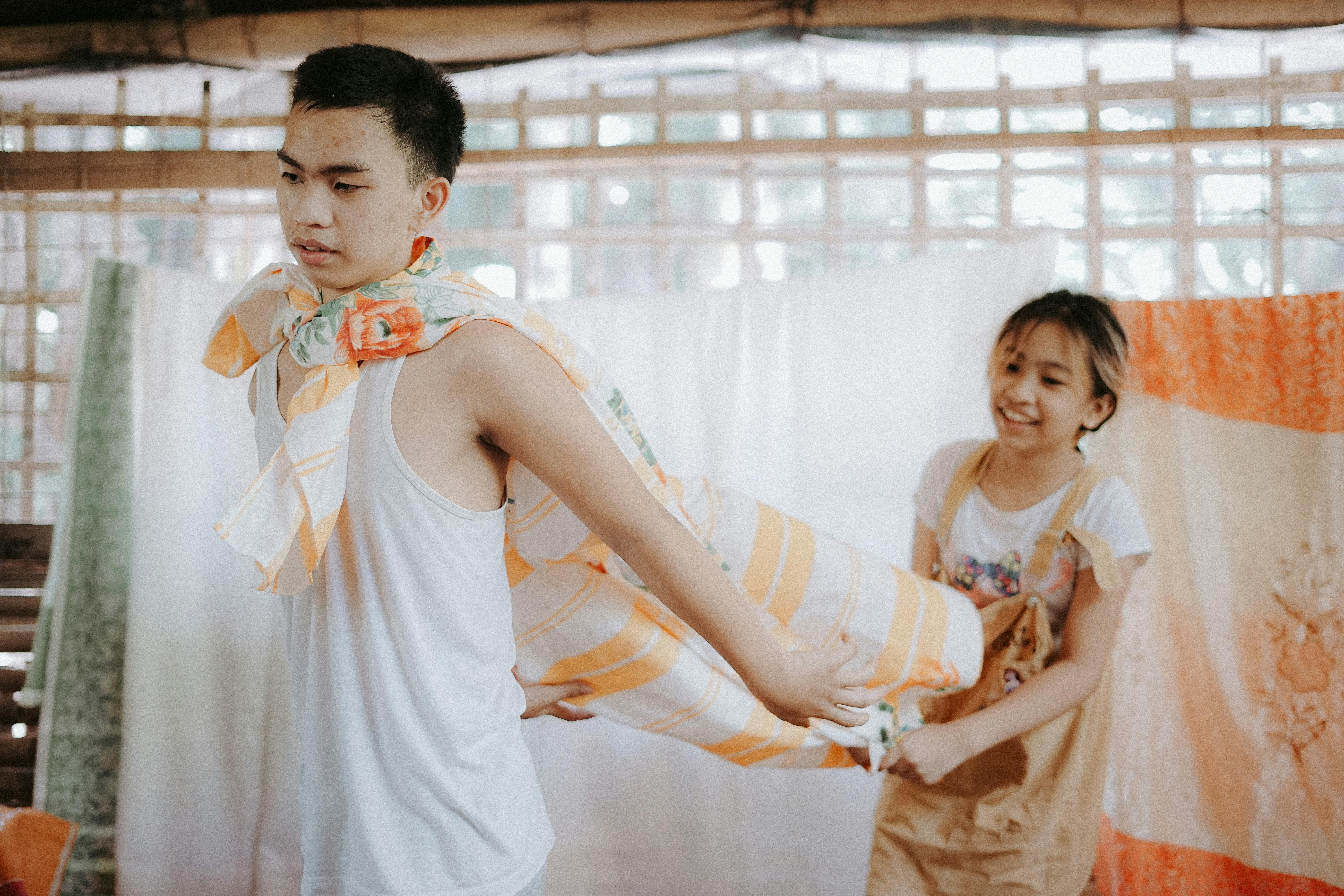 Girl and Boy Doing Carrying a Roll of Fabric · Free Stock Photo