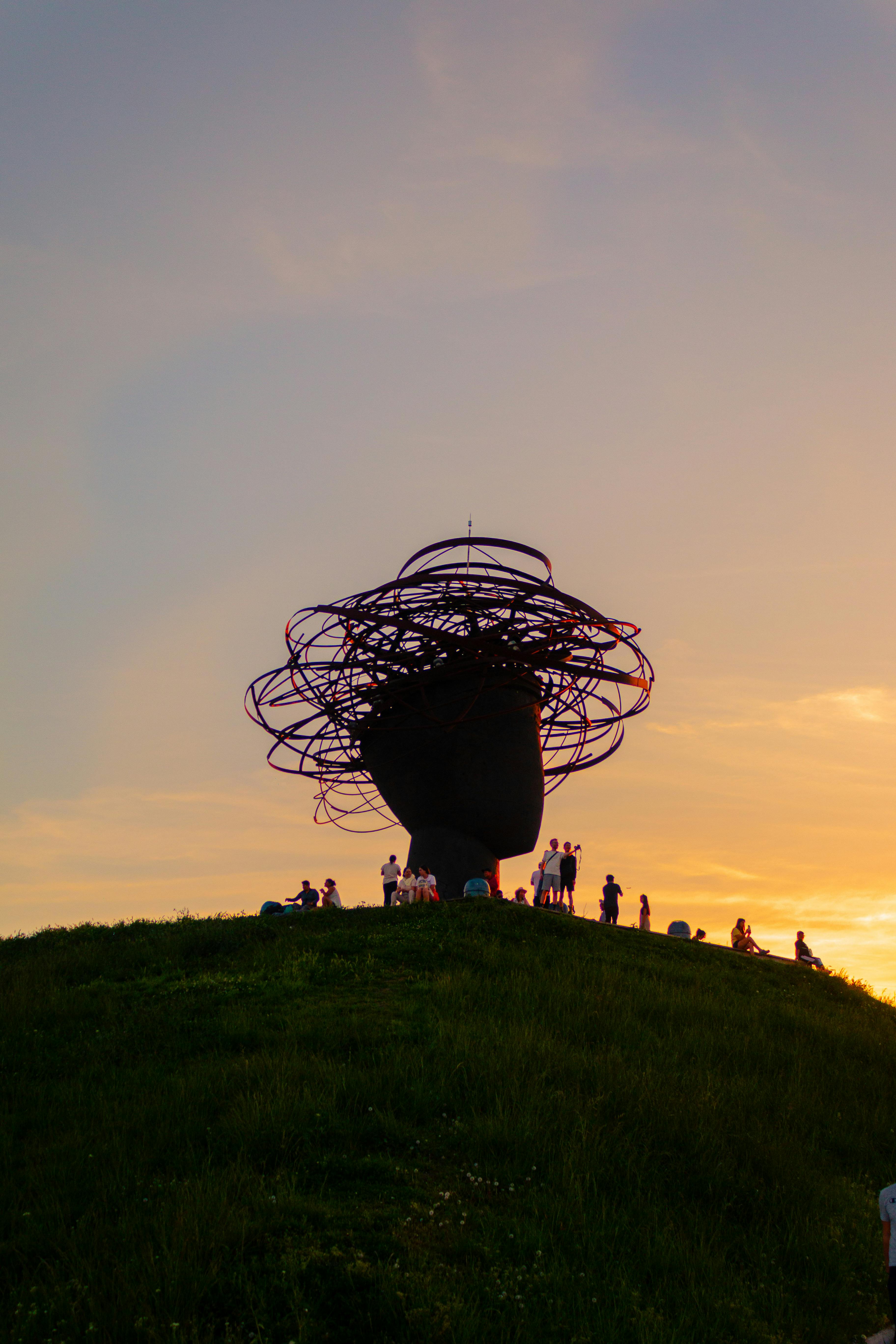 People Around a Sculpture on a Hill at Sunset · Free Stock Photo