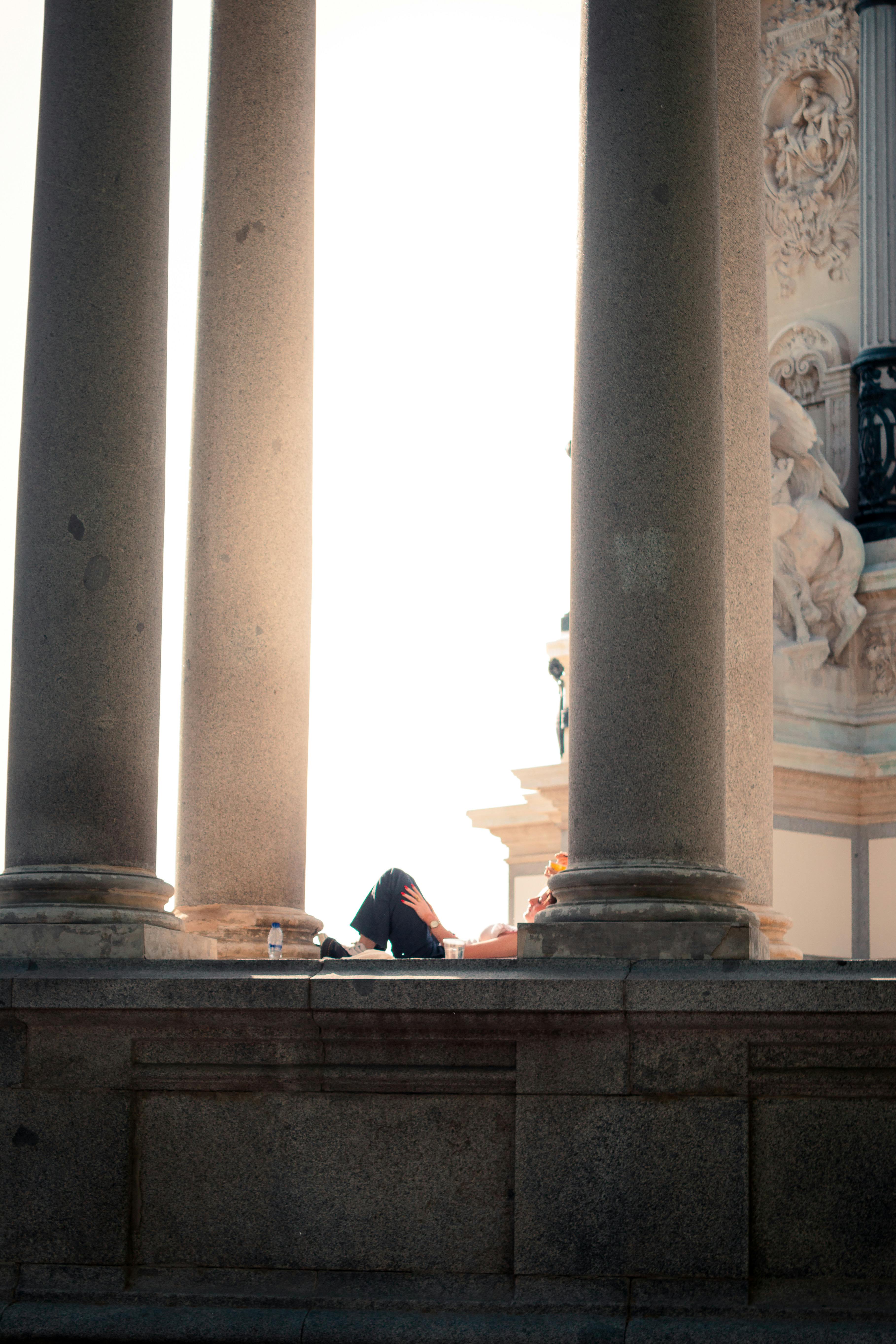 Person Lying Down behind Columns · Free Stock Photo