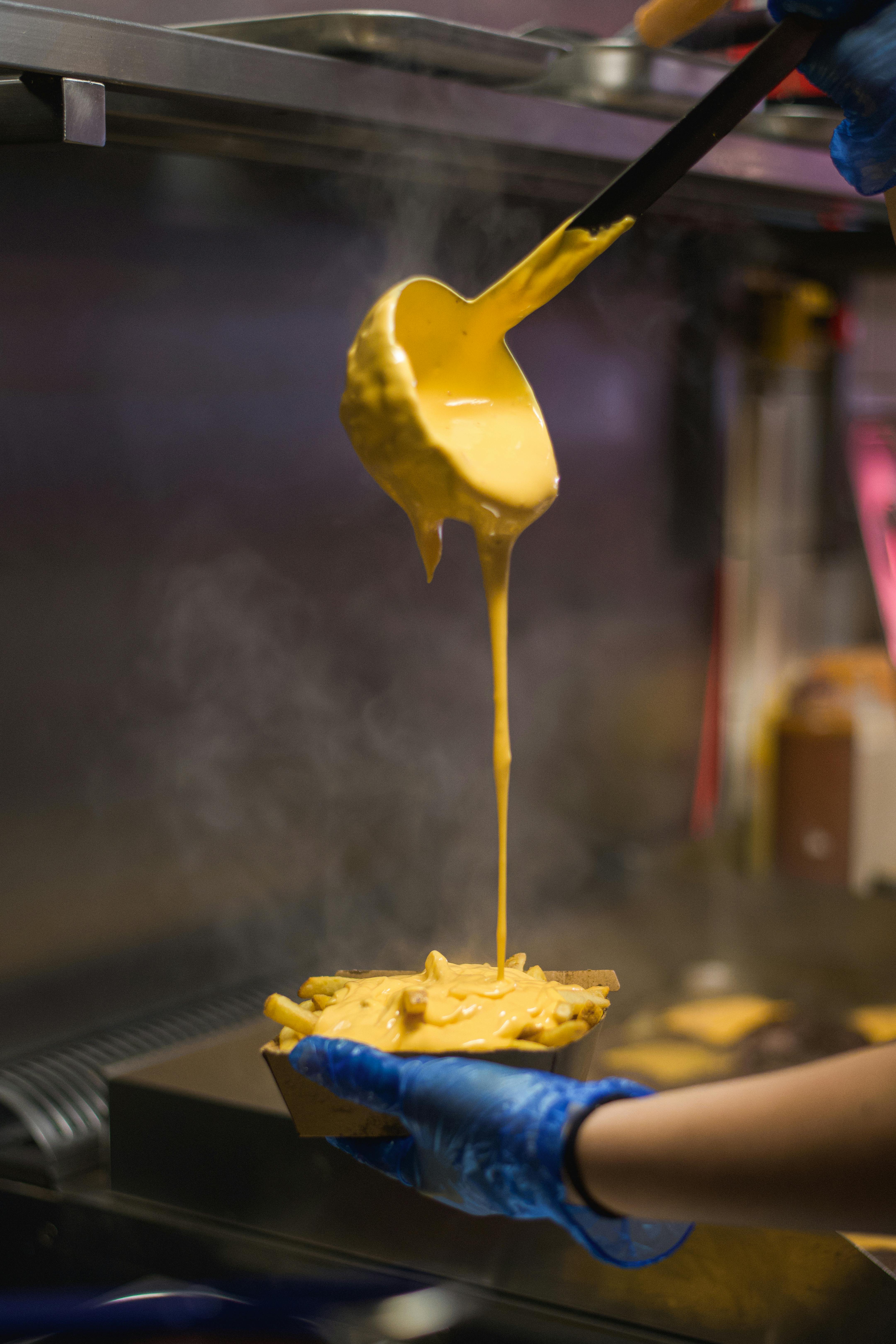Person Pouring Melted Cheese to Fries · Free Stock Photo
