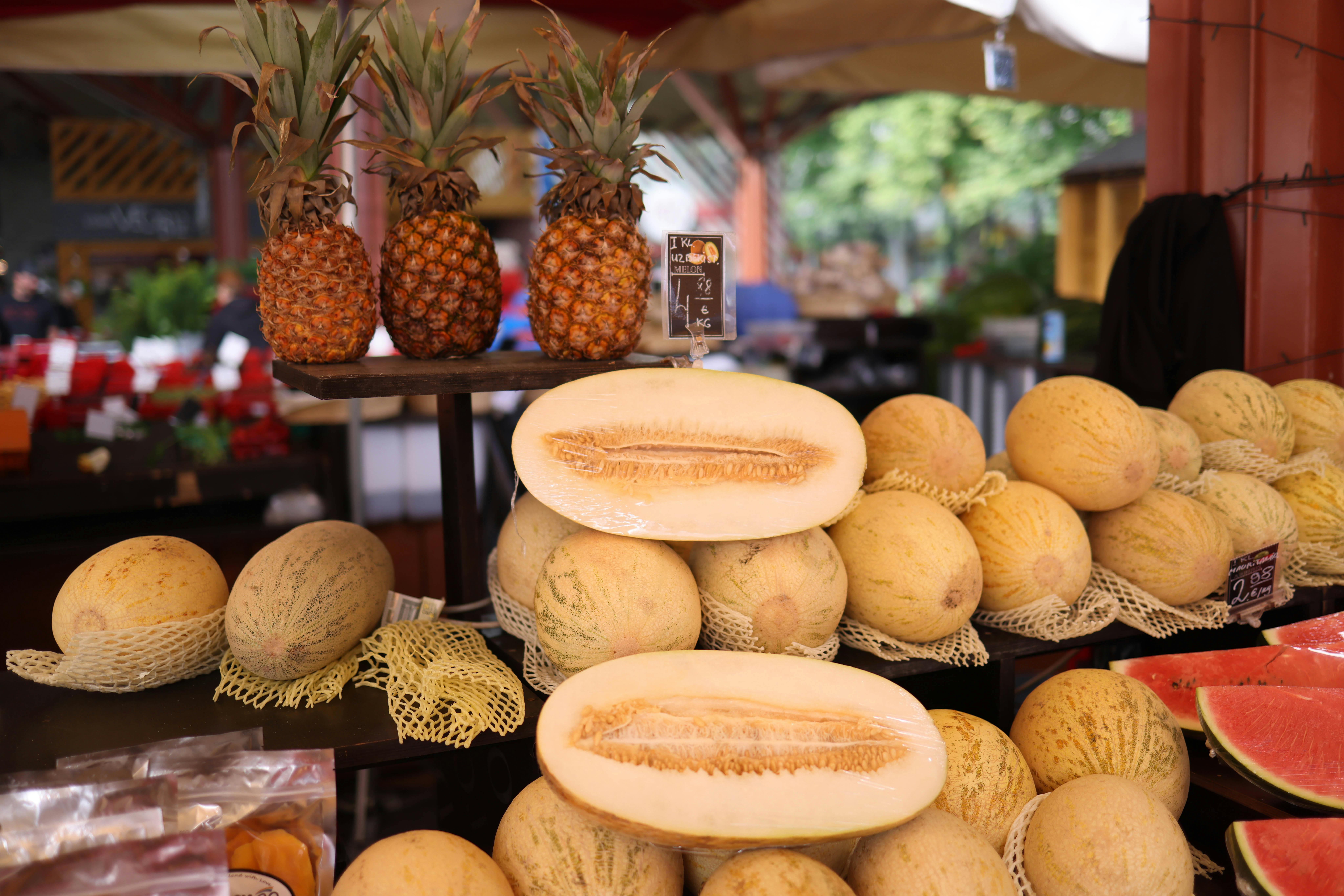 A display of melons and pineapples at a market · Free Stock Photo
