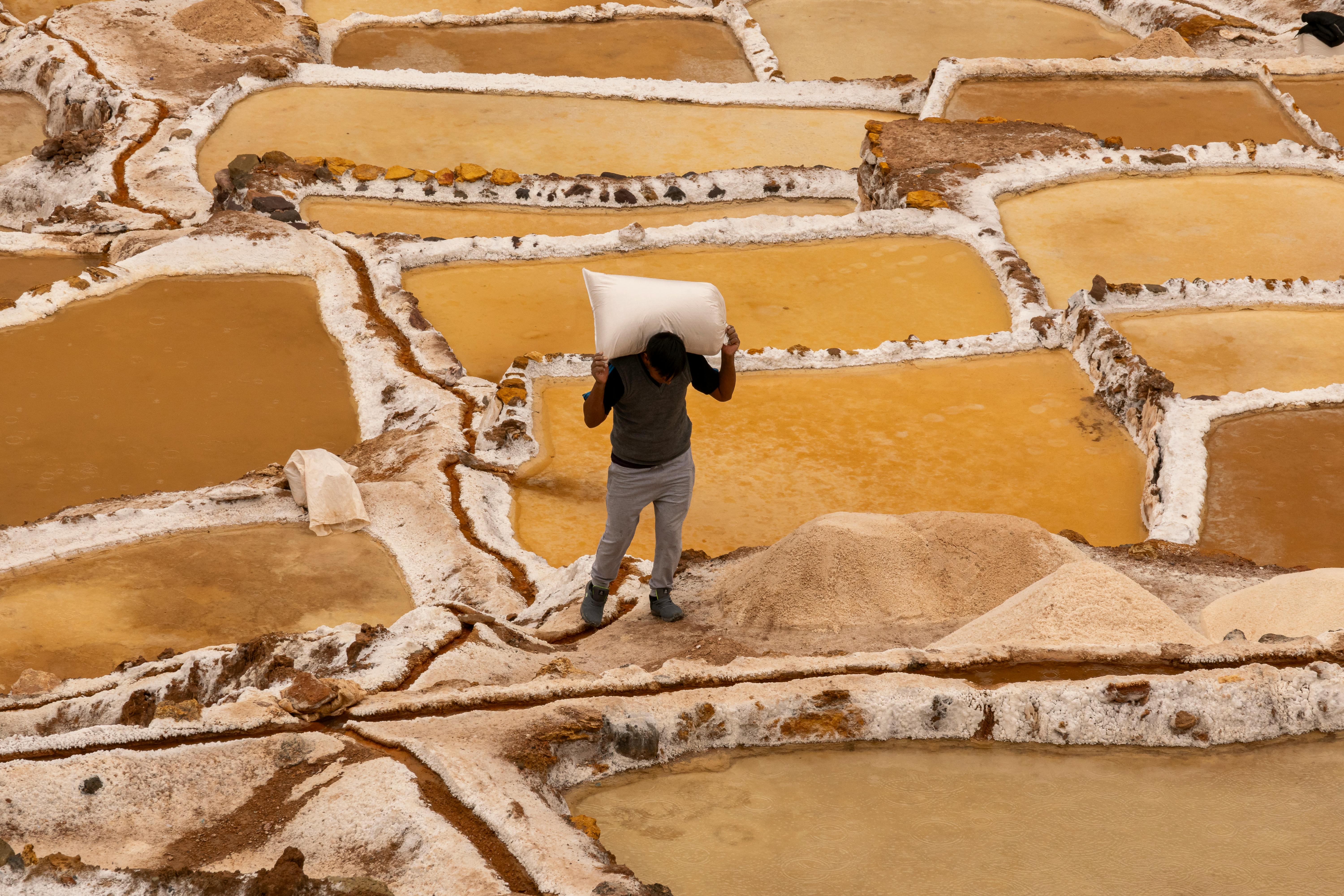 A man carrying a large sack of salt on his back · Free Stock Photo