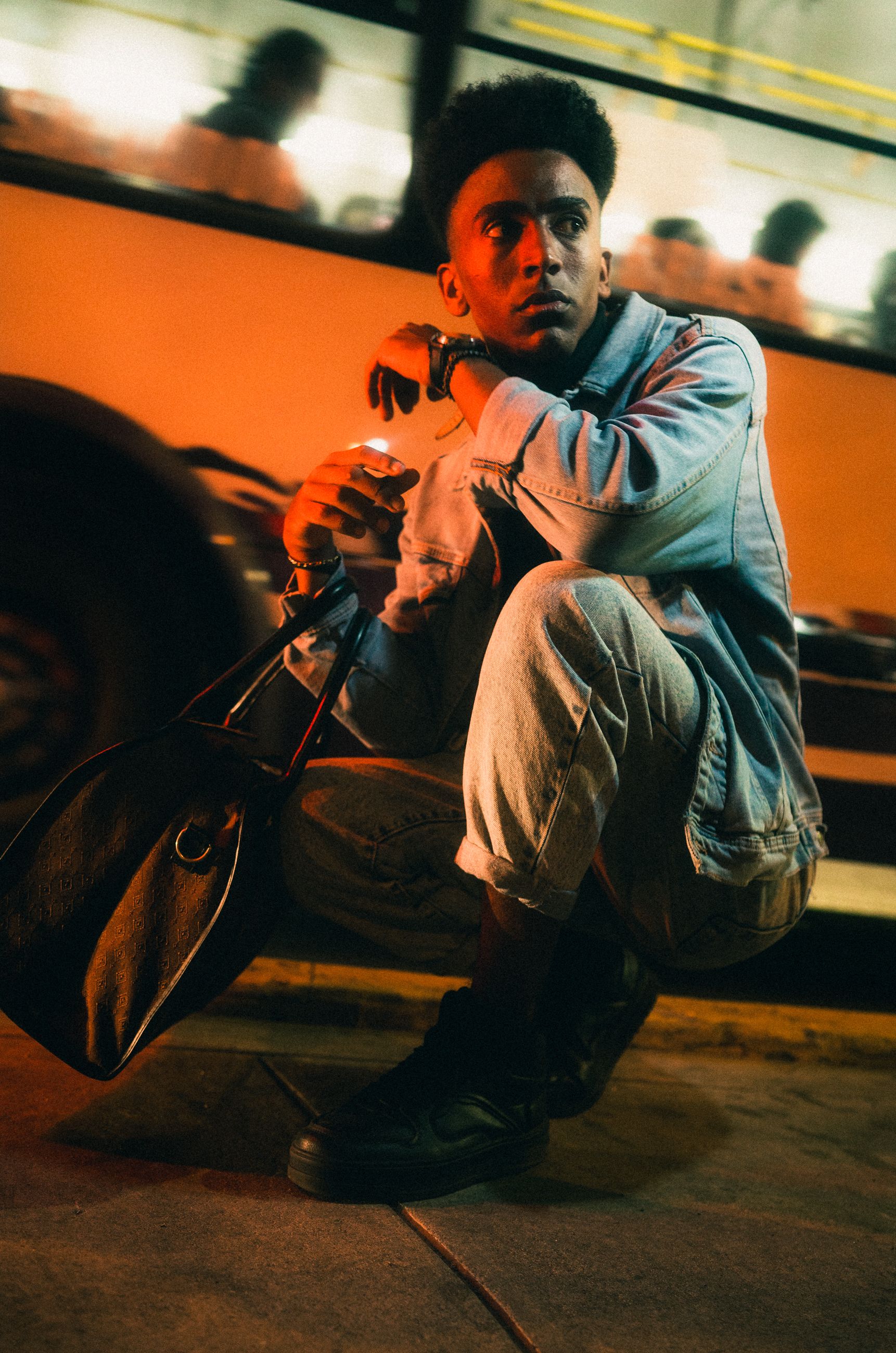 A Man Crouching on the Sidewalk on the Background of a Moving Bus ...