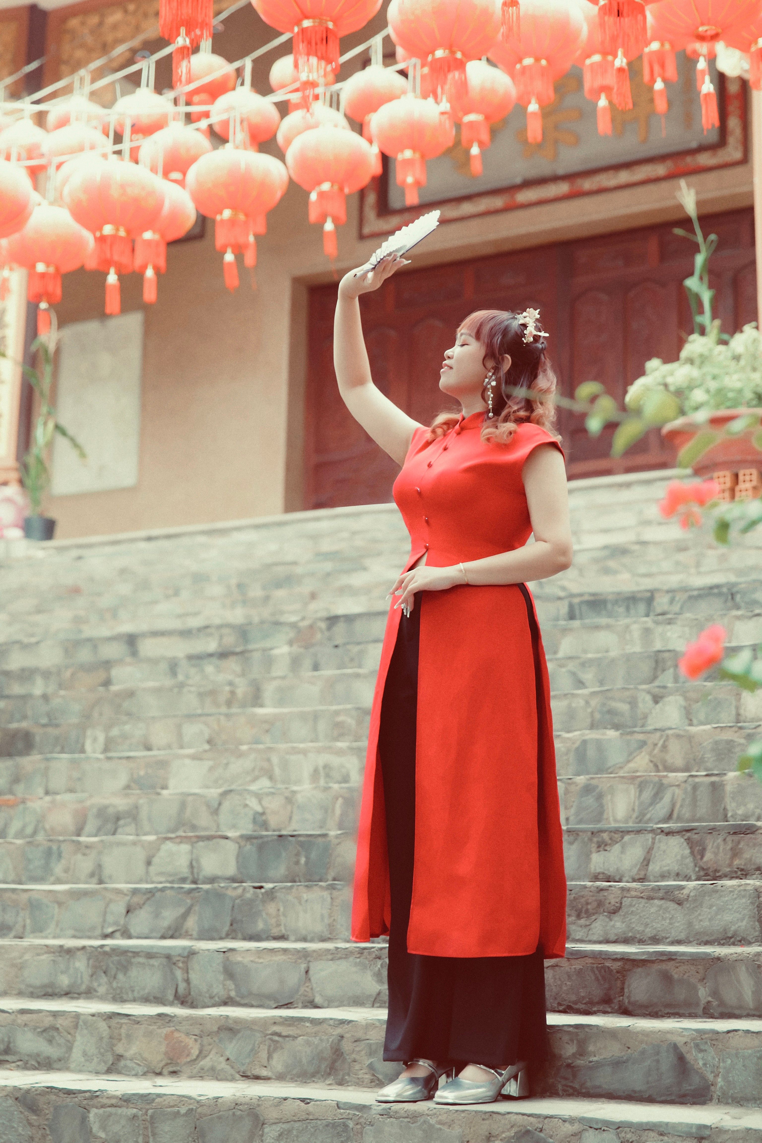 A woman in a red dress is holding up some lanterns · Free Stock Photo