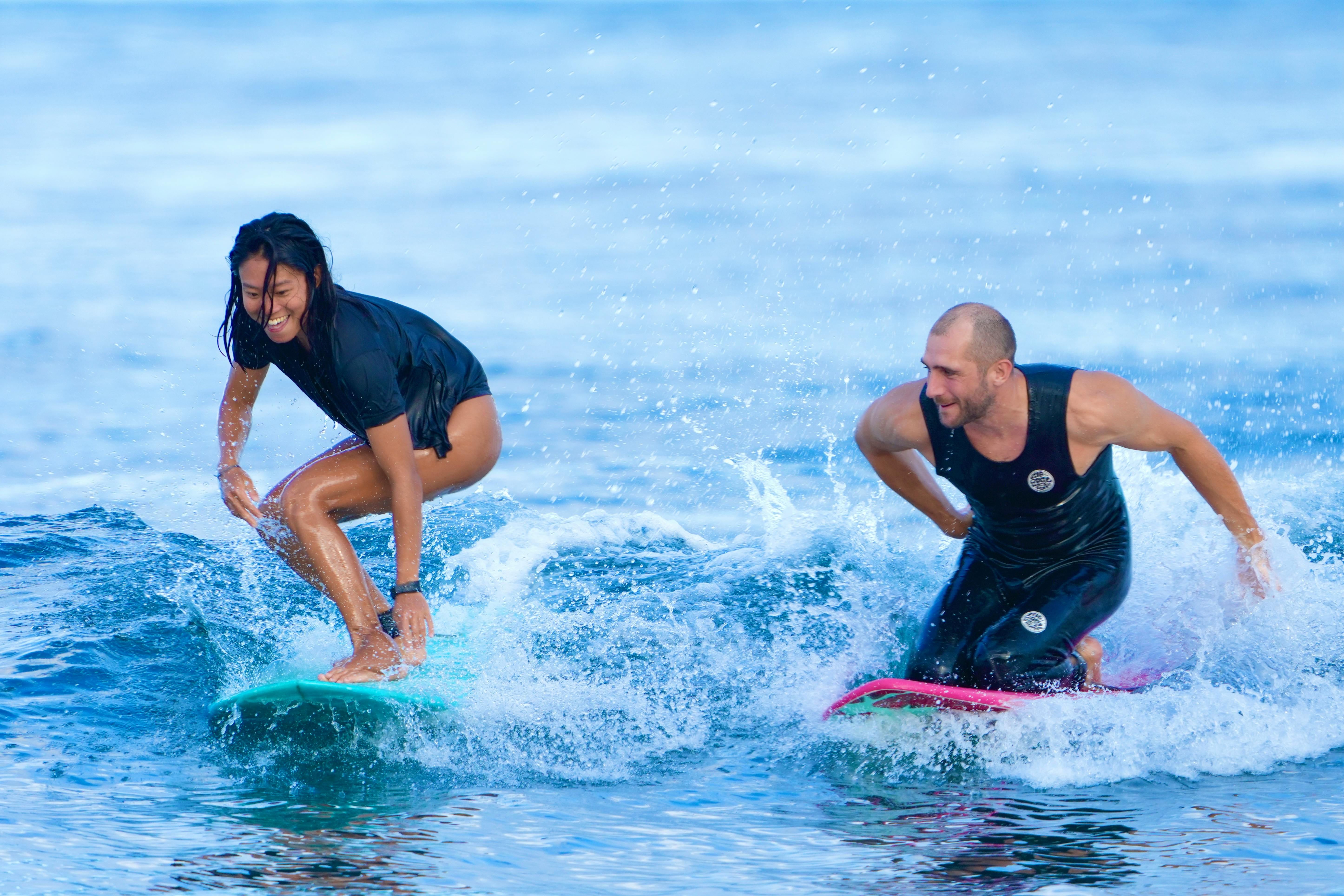 Woman and Man Surfing on Seashore · Free Stock Photo