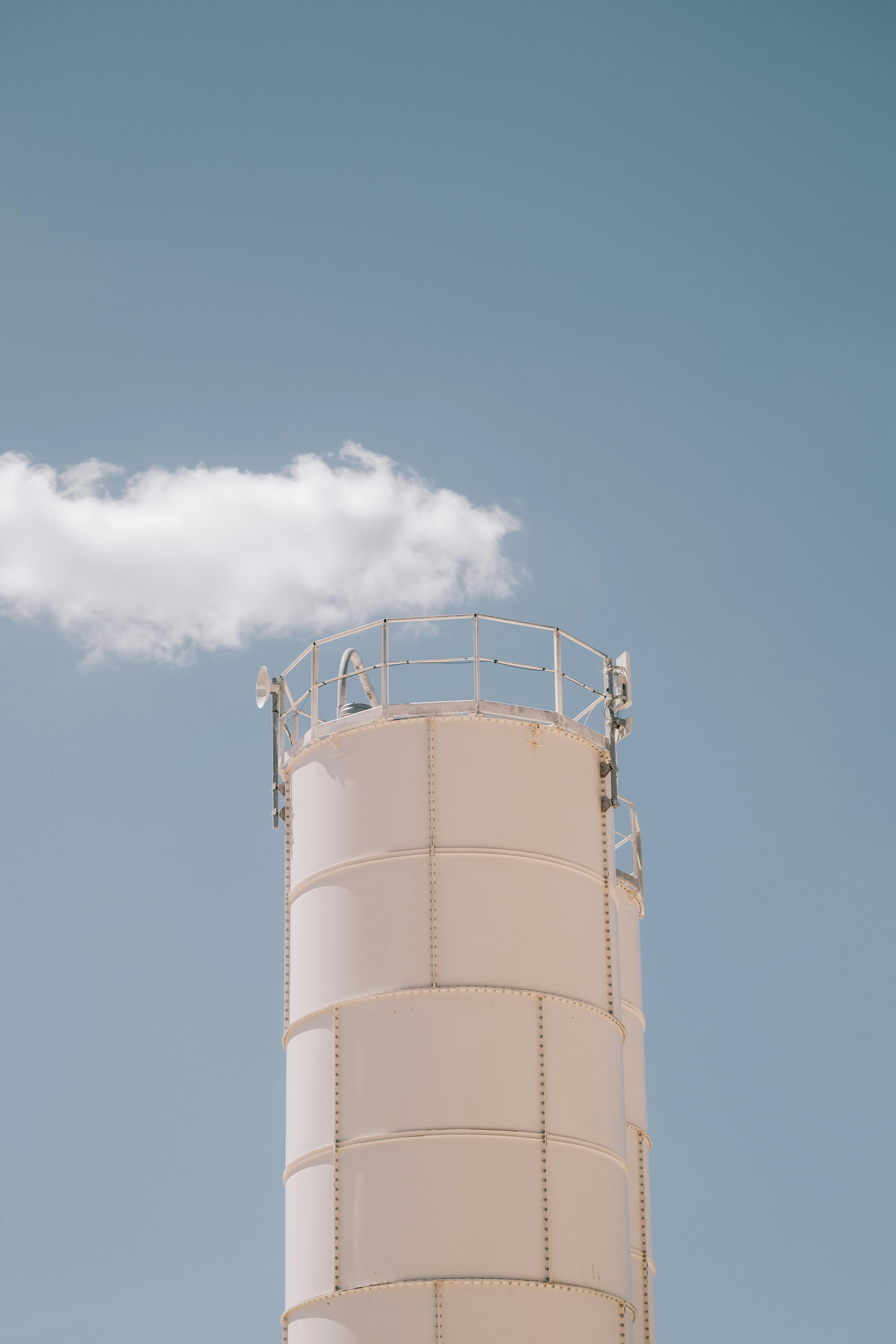 A white industrial tank with a cloud in the sky · Free Stock Photo