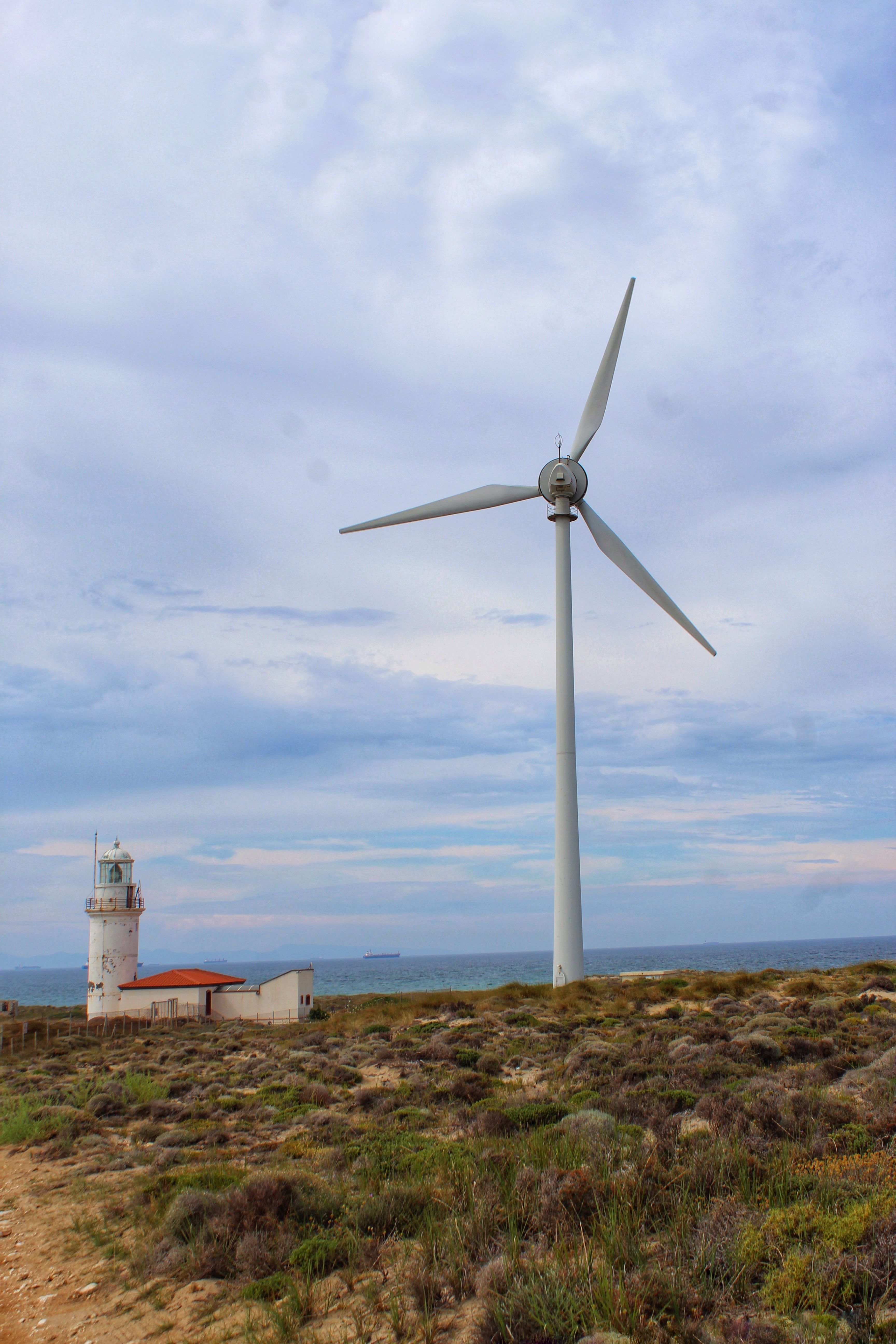 Wind Turbine by the Scenic Spot with a Lighthouse · Free Stock Photo
