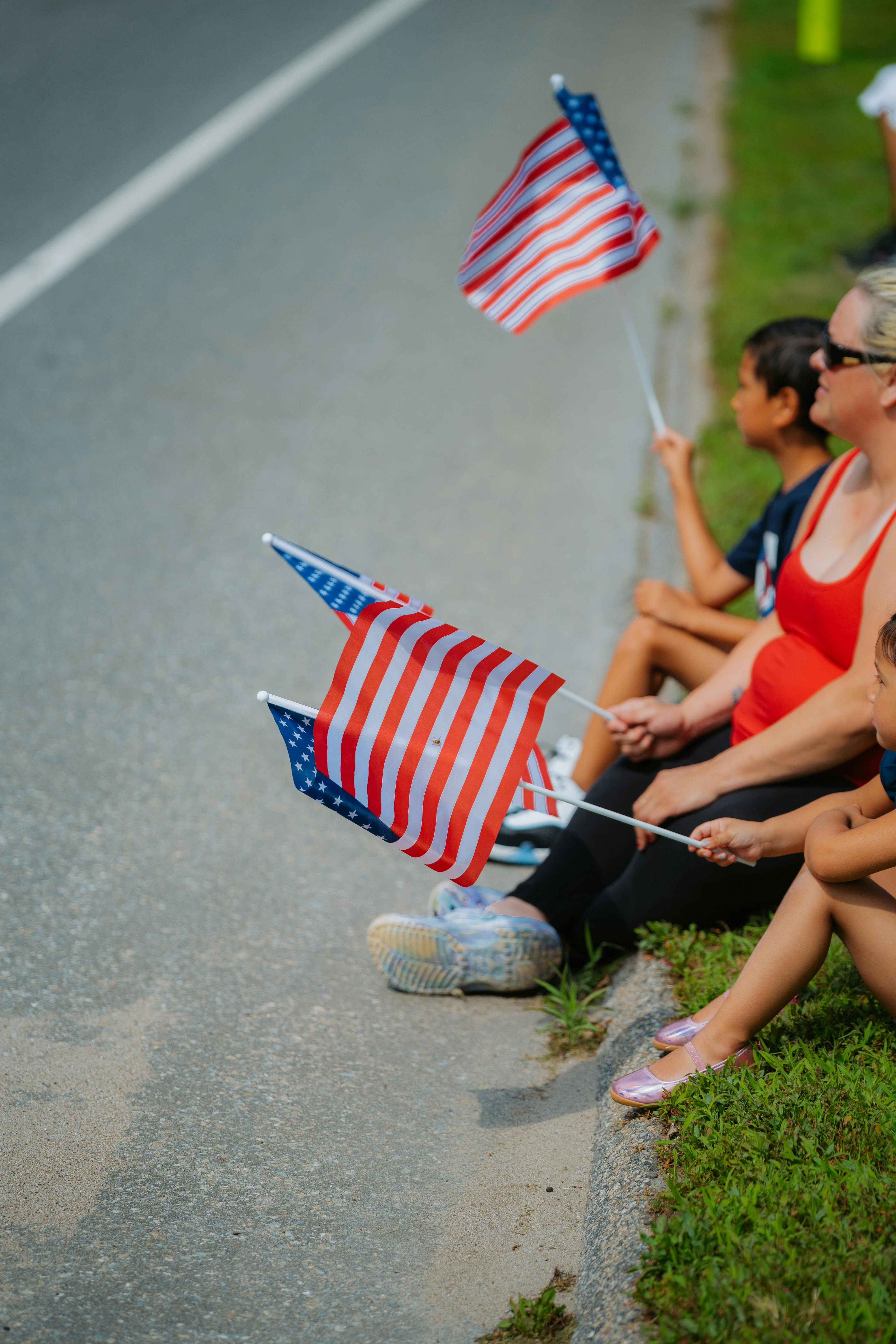 Sitting on Curb Woman and Boys Holding US Flags · Free Stock Photo