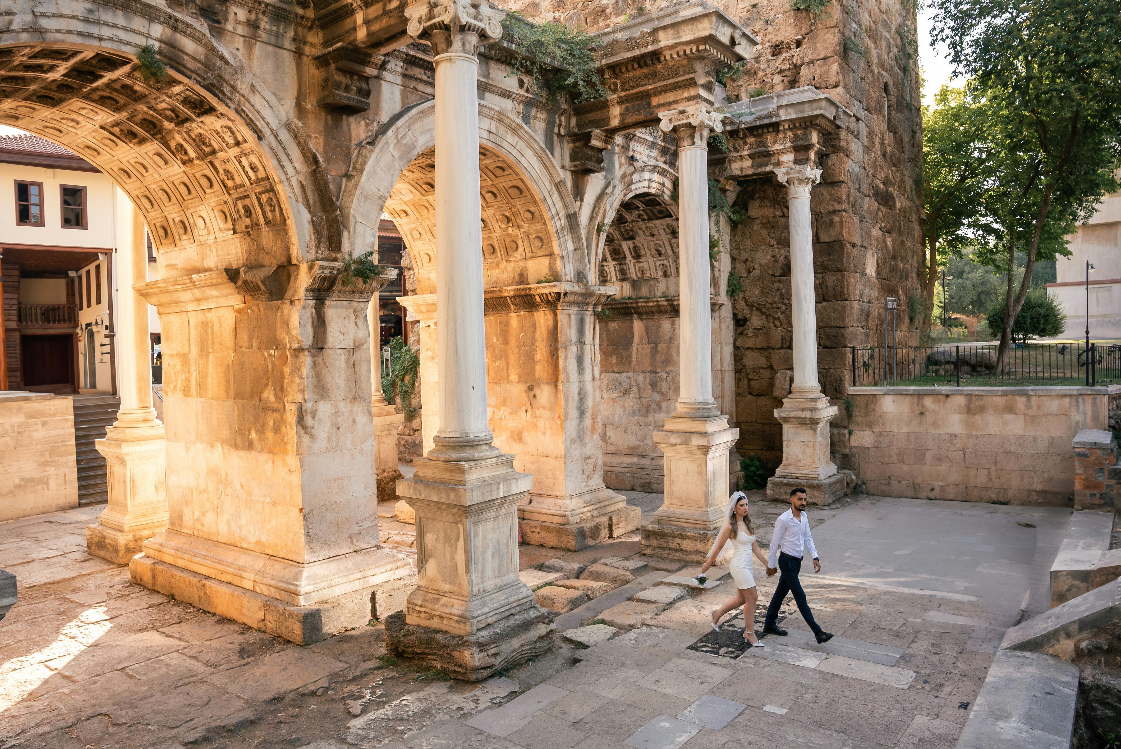 Walking Newlyweds Holding Hands among Ancient Ruins · Free Stock Photo