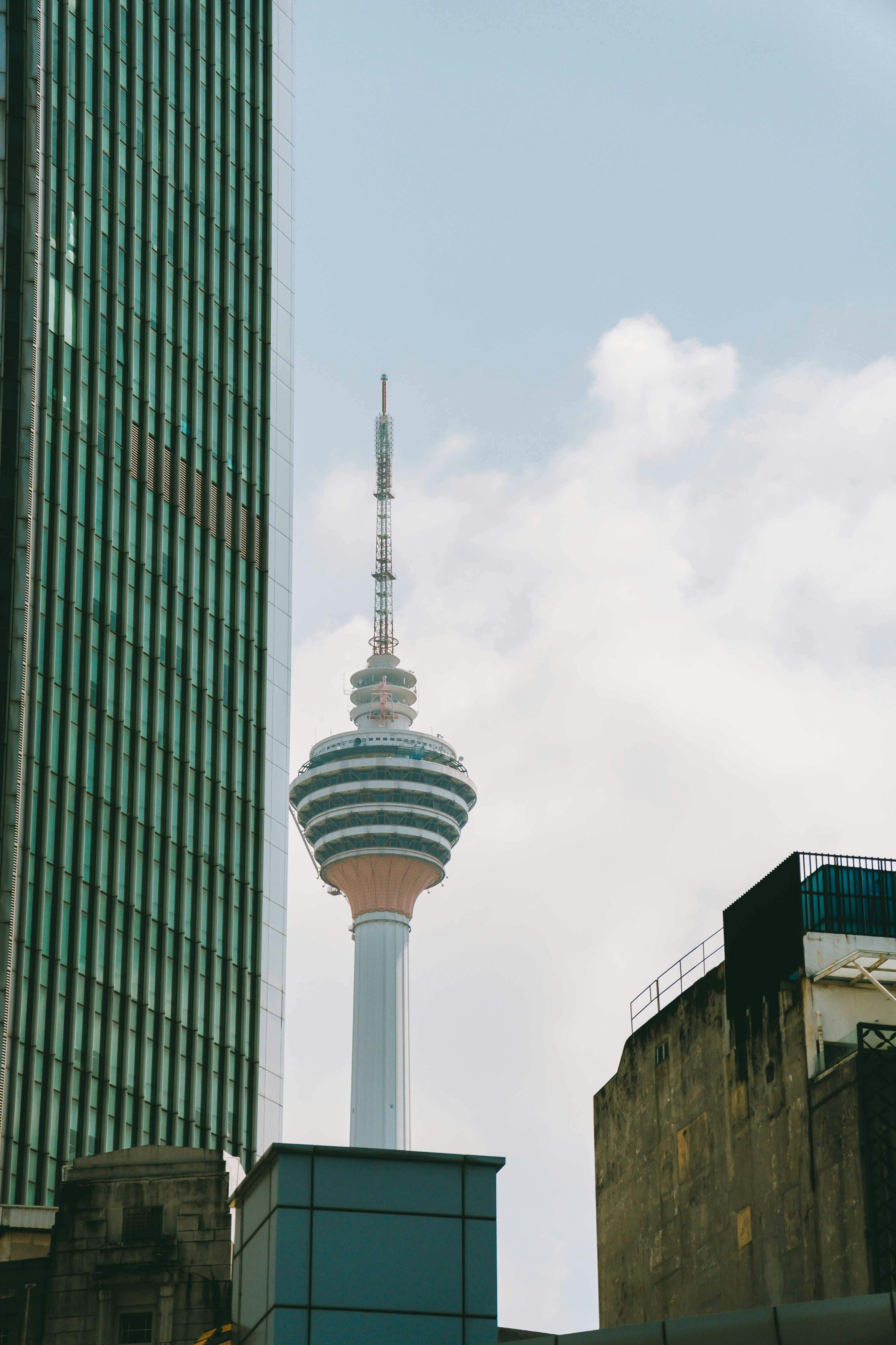 Man Standing While Facing Concrete Buildings · Free Stock Photo