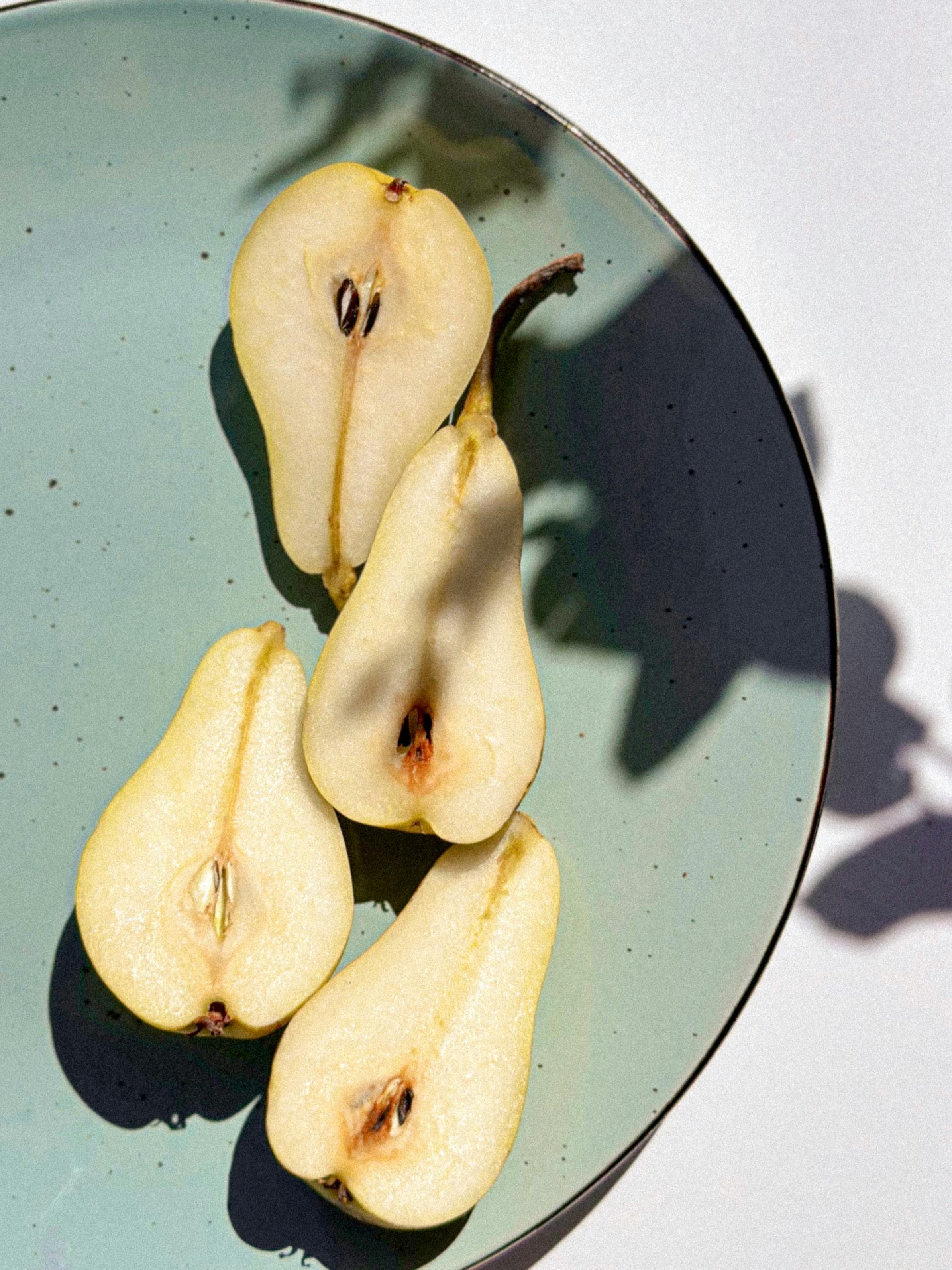 Shadow Cast on Pear Halves Lying on Ceramic Plate · Free Stock Photo