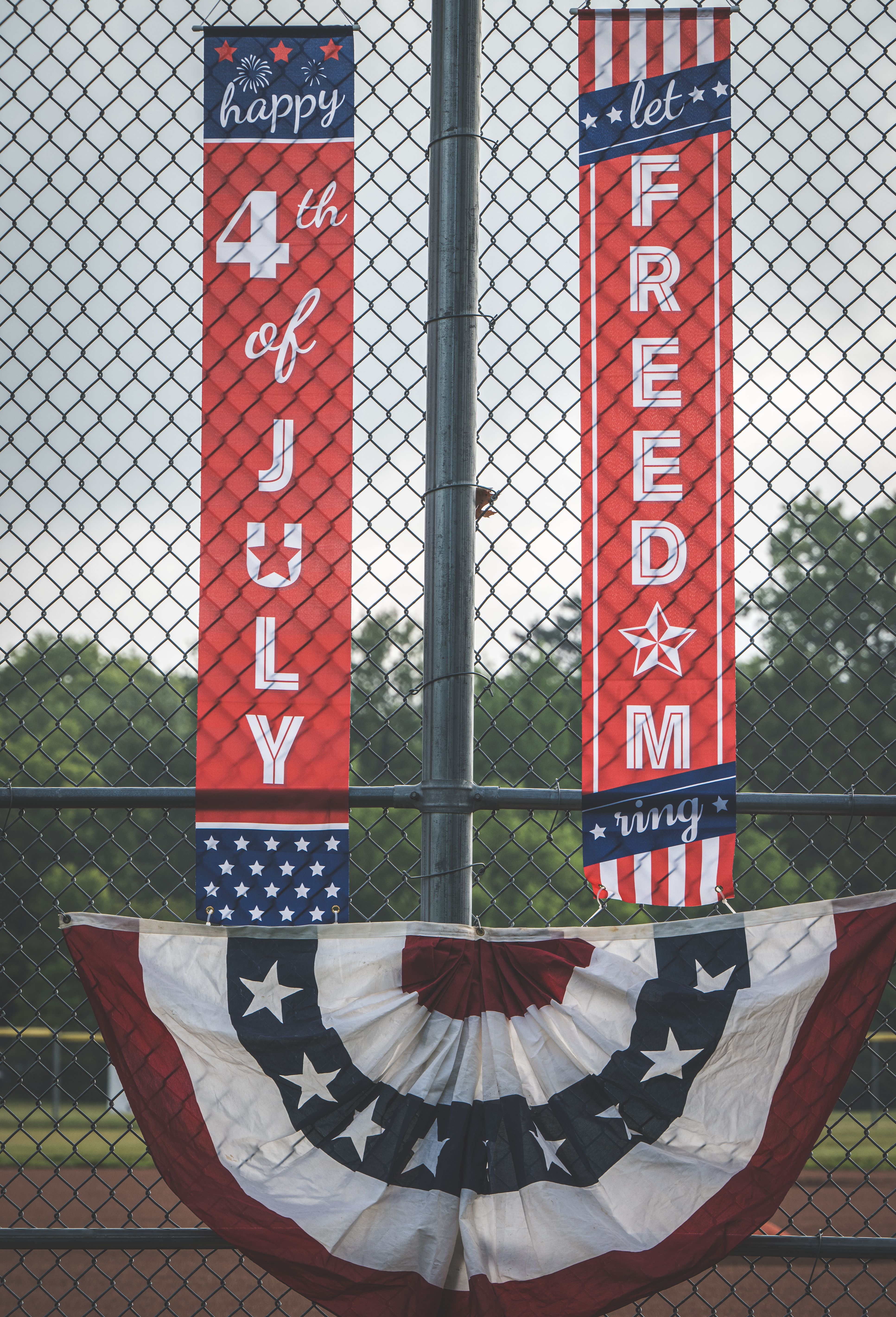 A patriotic banner hanging from a fence with the words freedom and ...