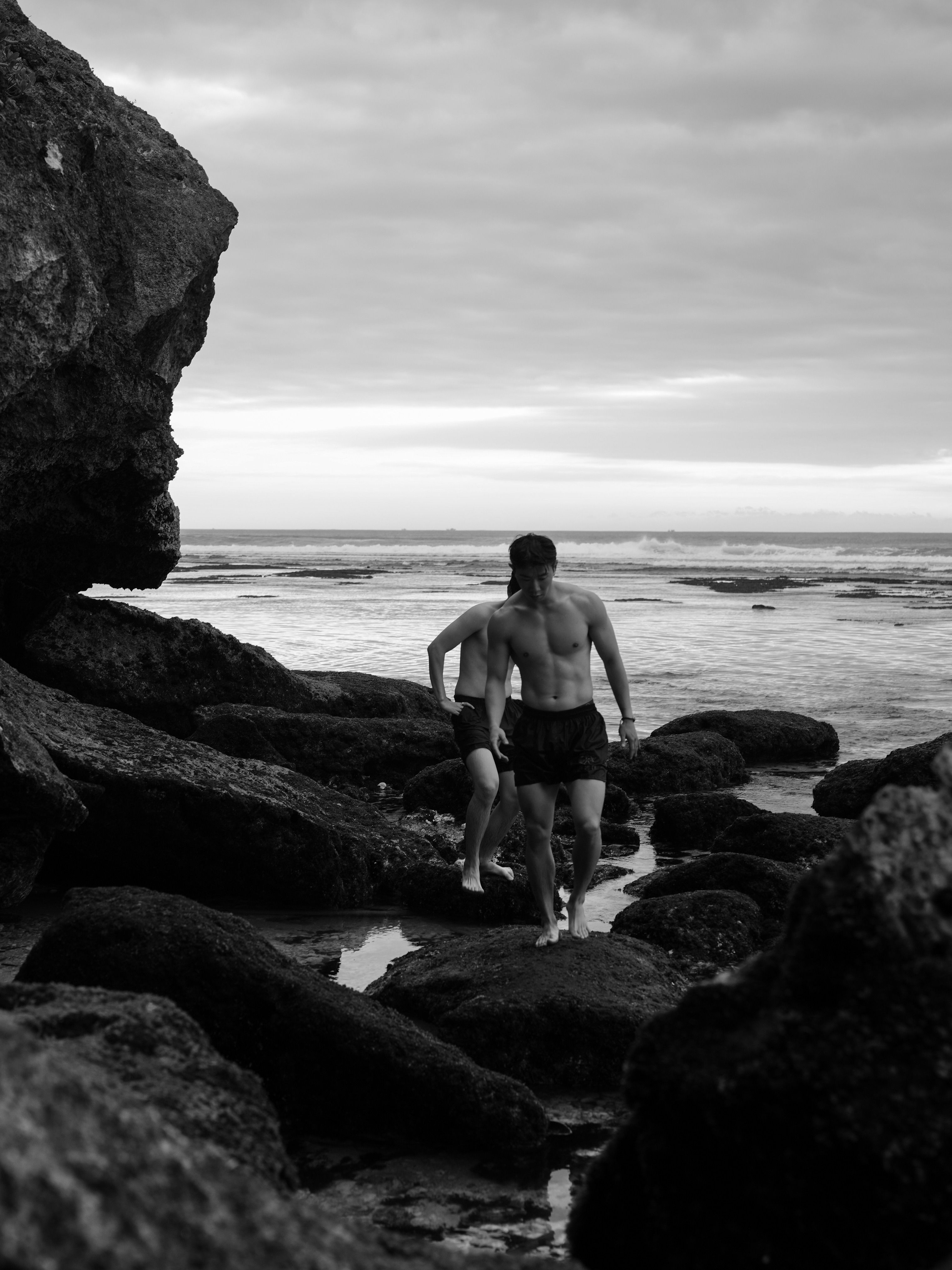 Two Young Men Walking on Rocks by the Sea · Free Stock Photo