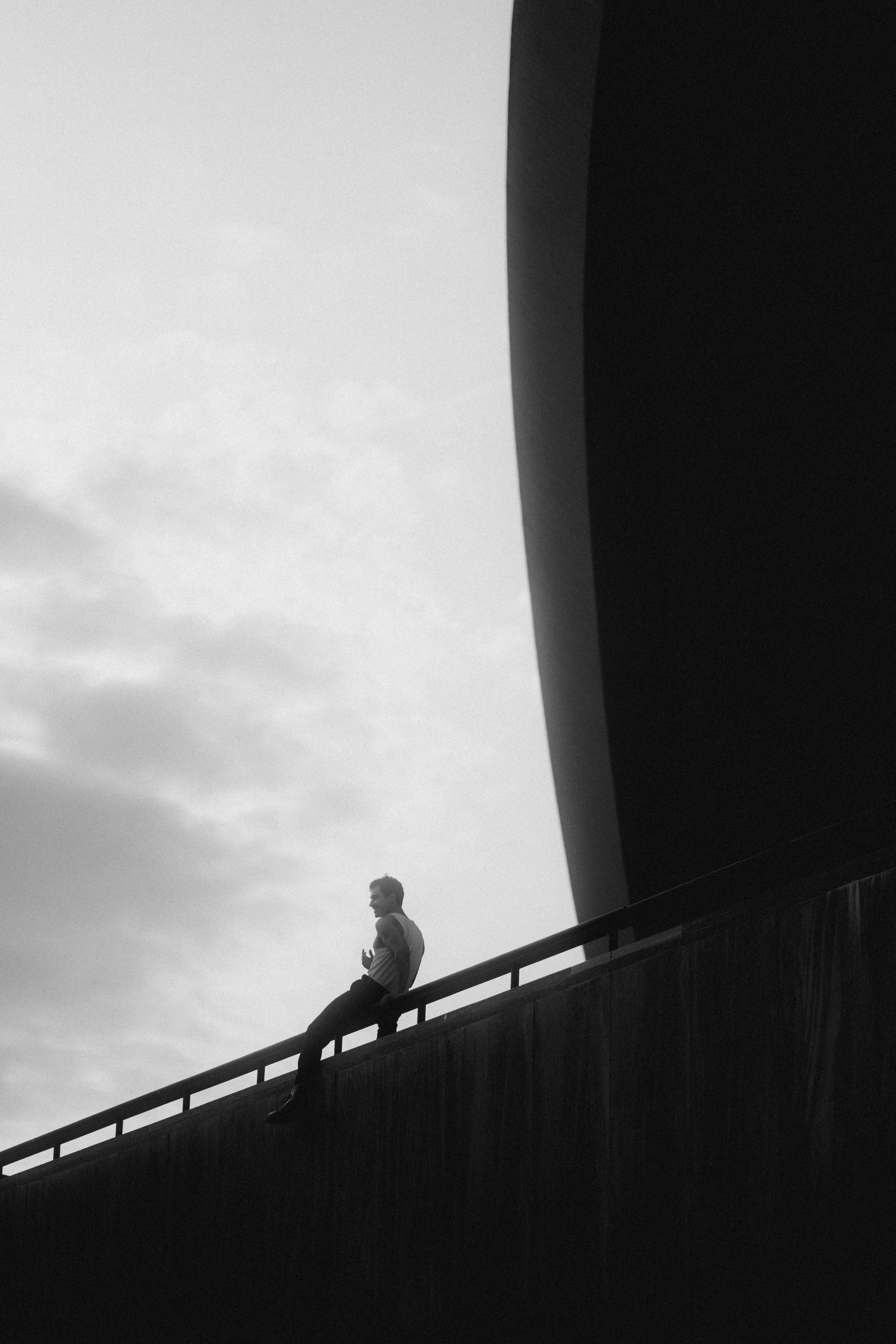 A person sitting on a ledge looking out over the city · Free Stock Photo