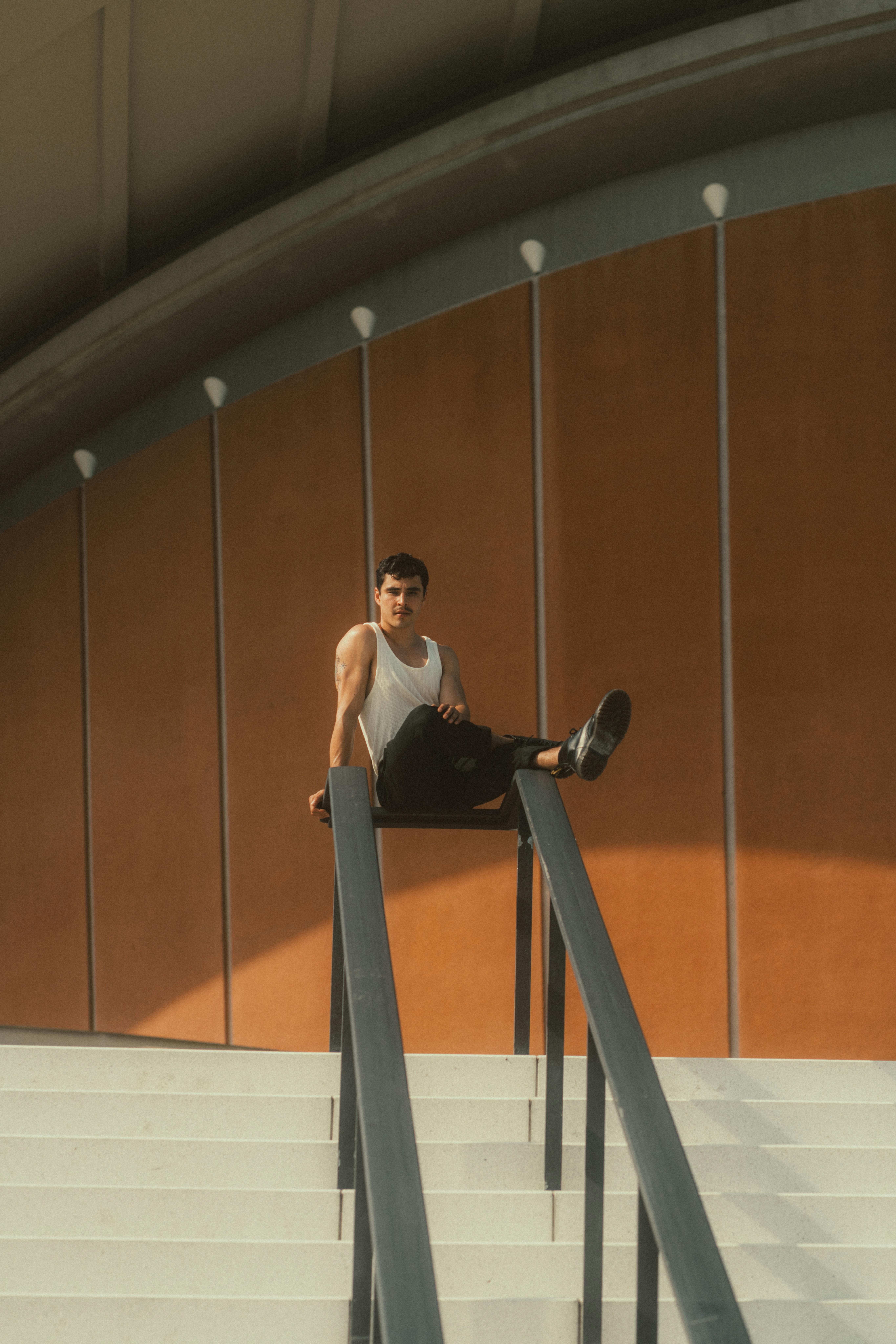 Muscular Man in White Tank Top Sitting on Staircase Railing · Free ...