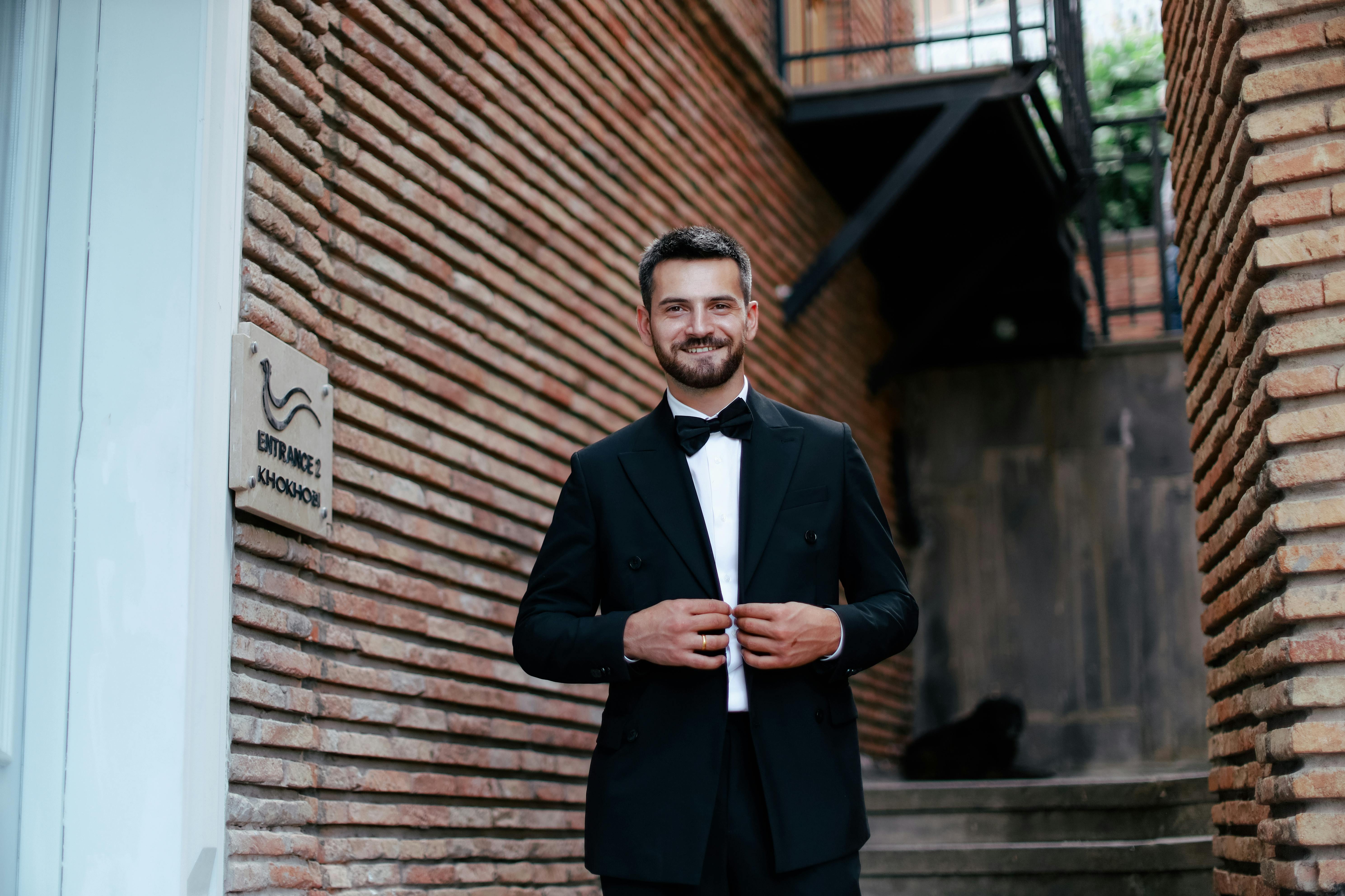 The Groom Standing between Walls of Building and Smiling · Free Stock Photo