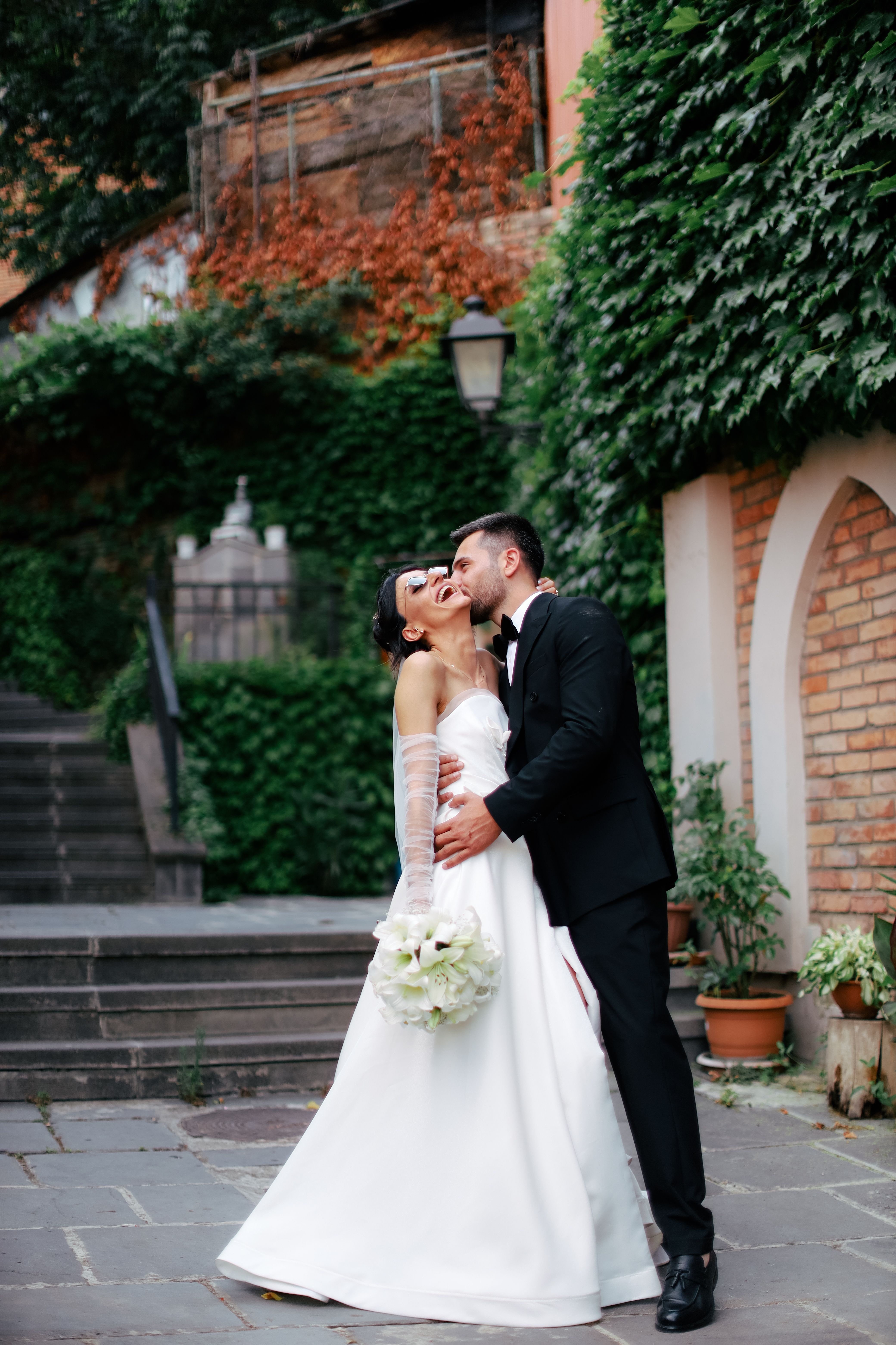 The Bride and Groom Kissing and Smiling while Standing on an Alley in a ...