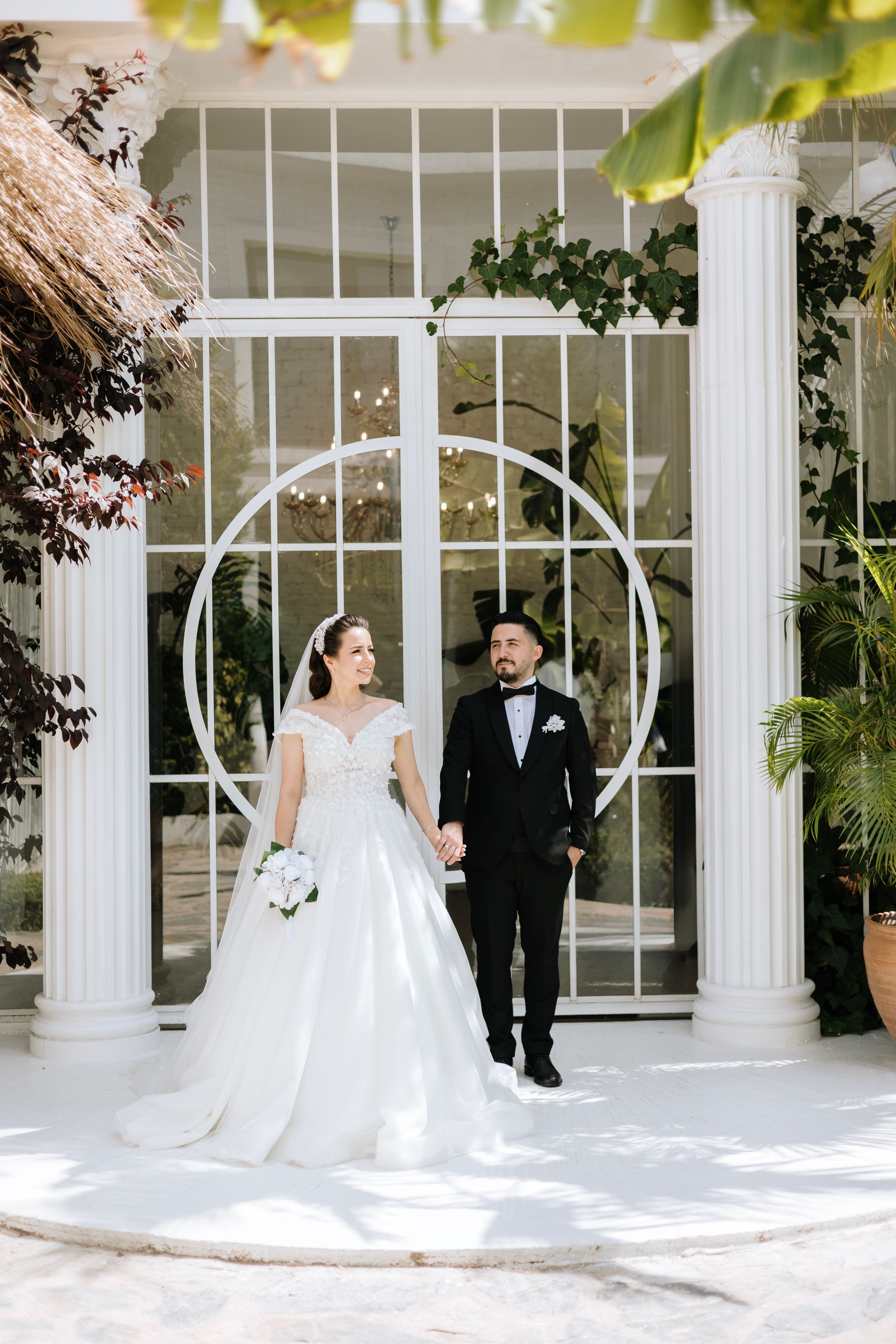 A bride and groom standing in front of a white building · Free Stock Photo