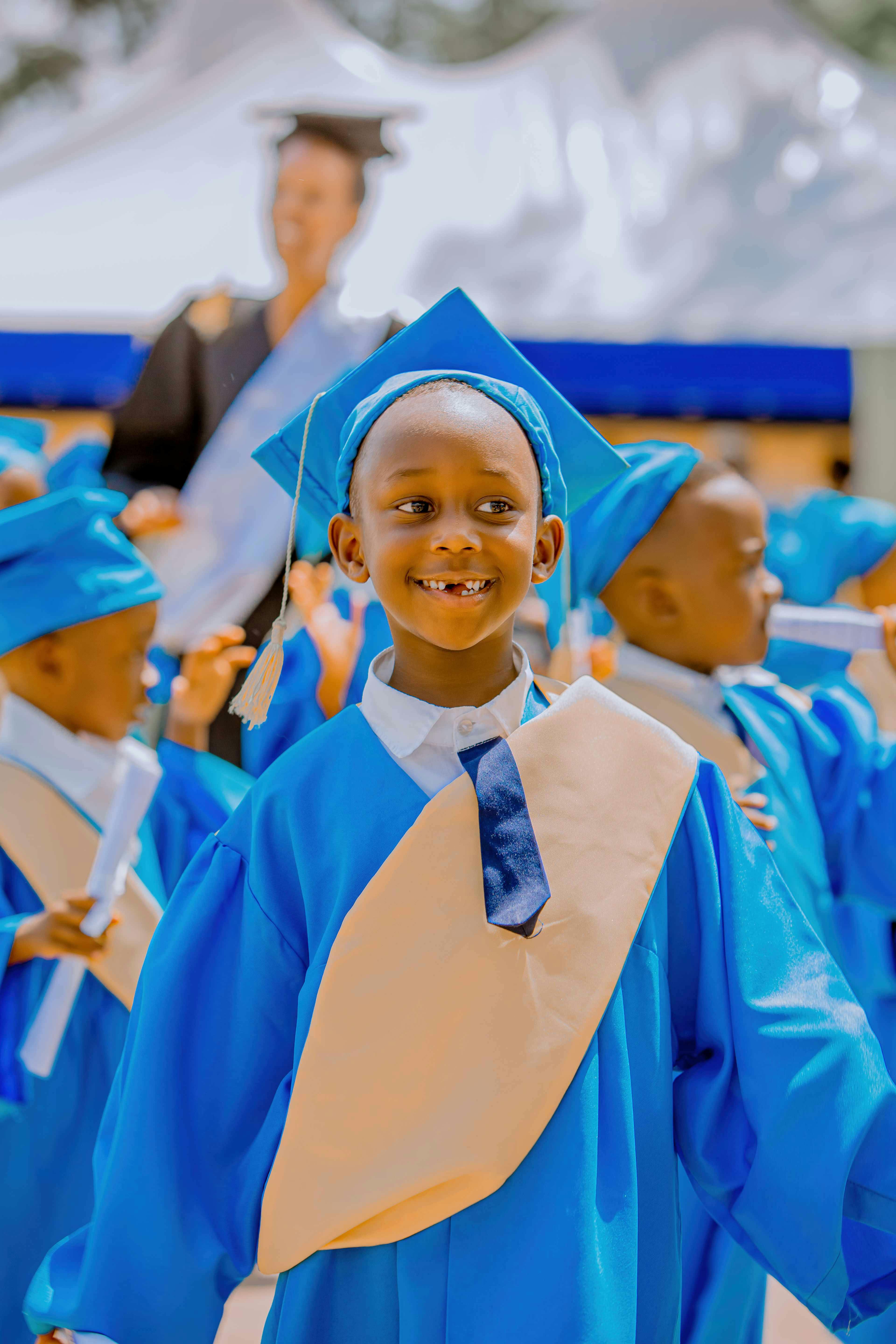 A Happy Boy Wearing a Graduation Gown and a Mortarboard · Free Stock Photo
