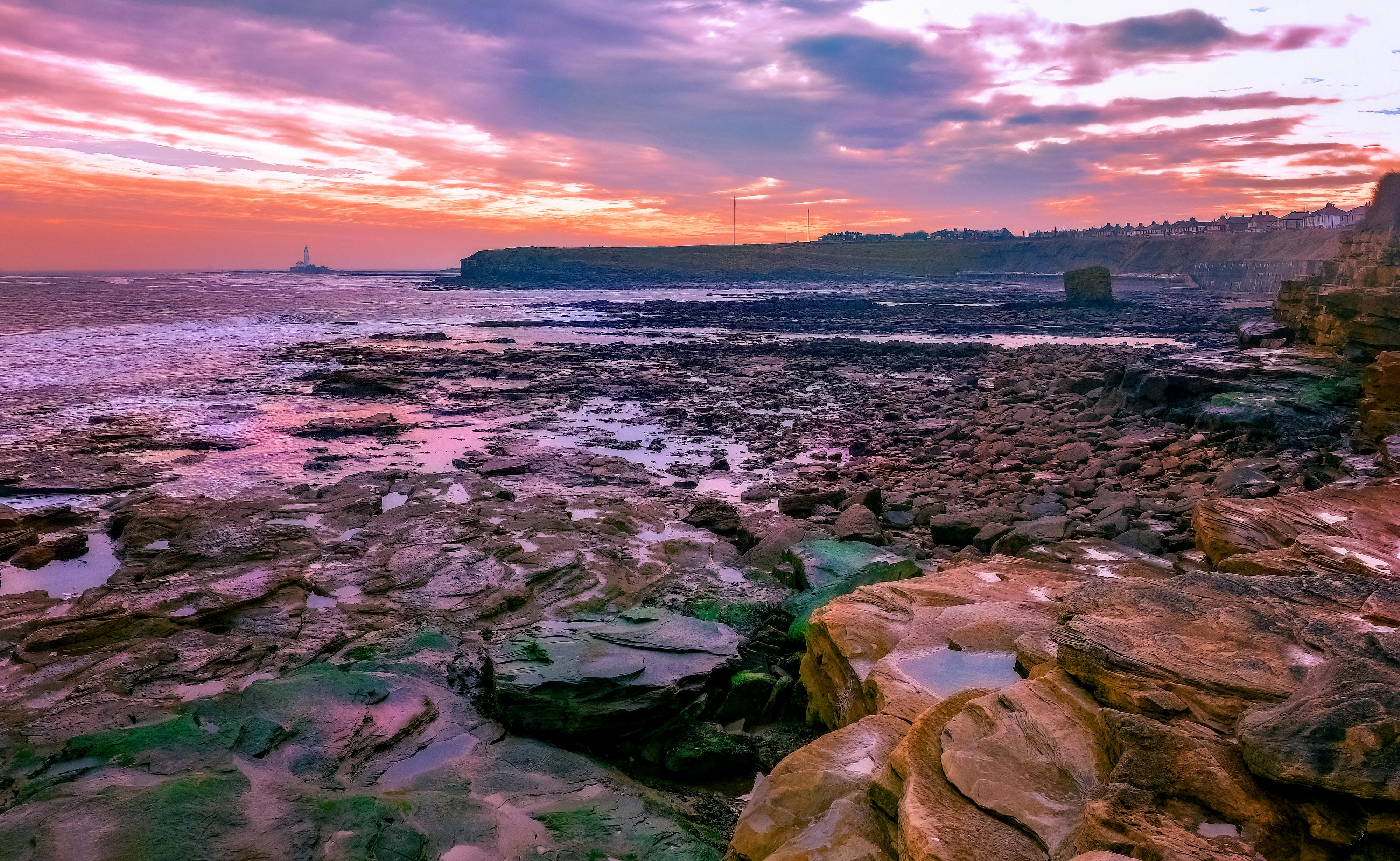 A sunset over the ocean with rocks and rocks · Free Stock Photo