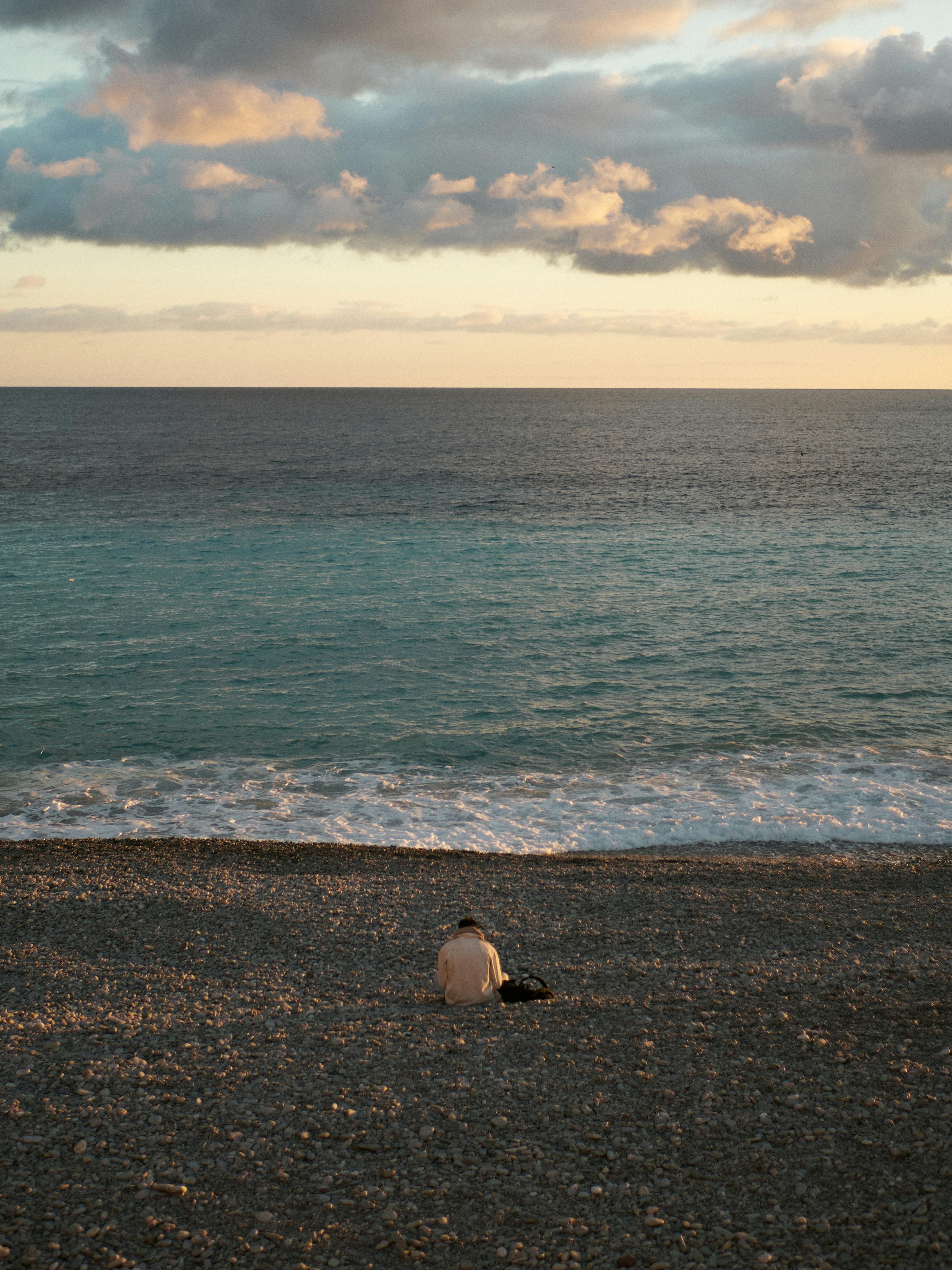 Back View of a Person Sitting Alone on a Beach · Free Stock Photo