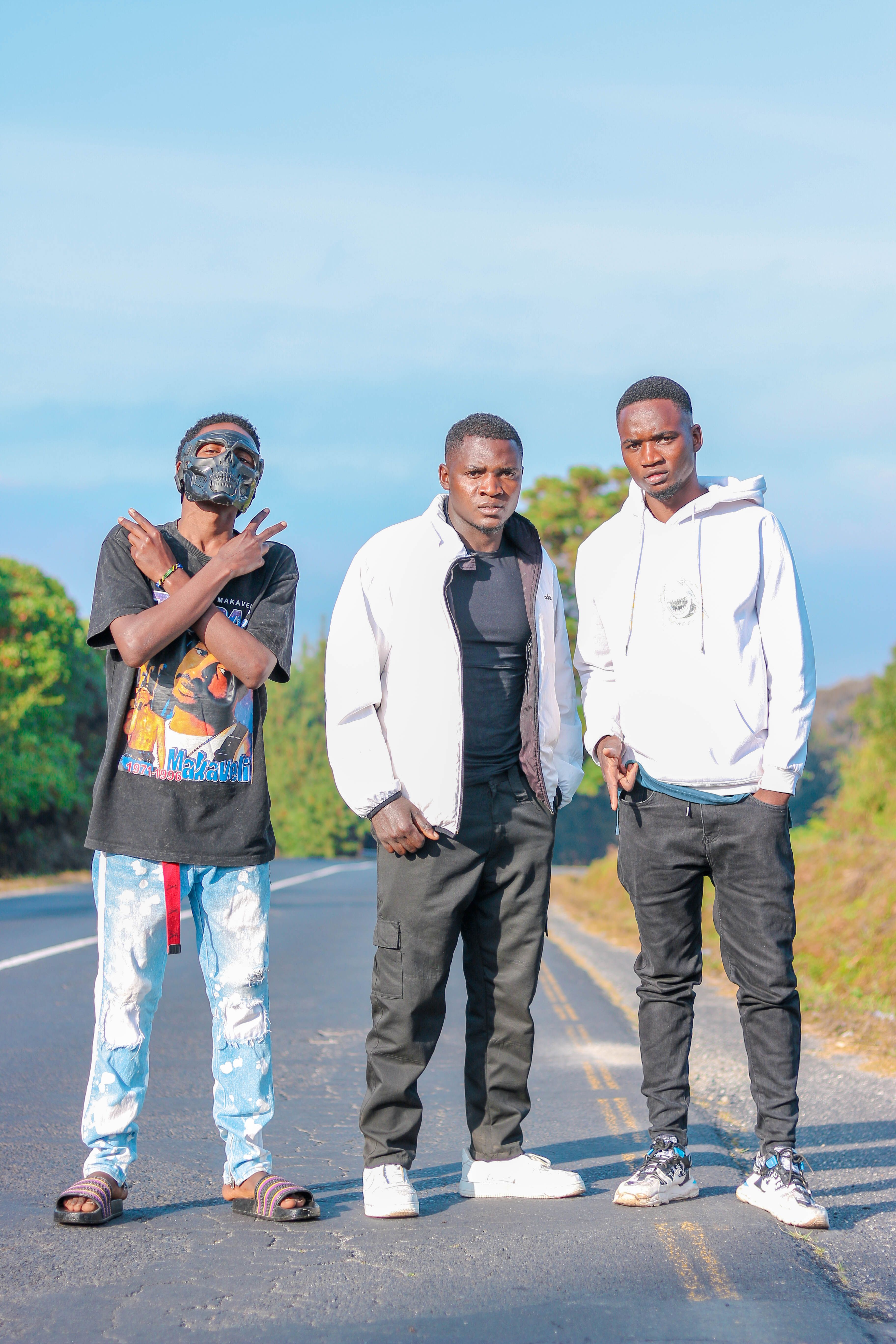 Three young men standing on the side of a road · Free Stock Photo