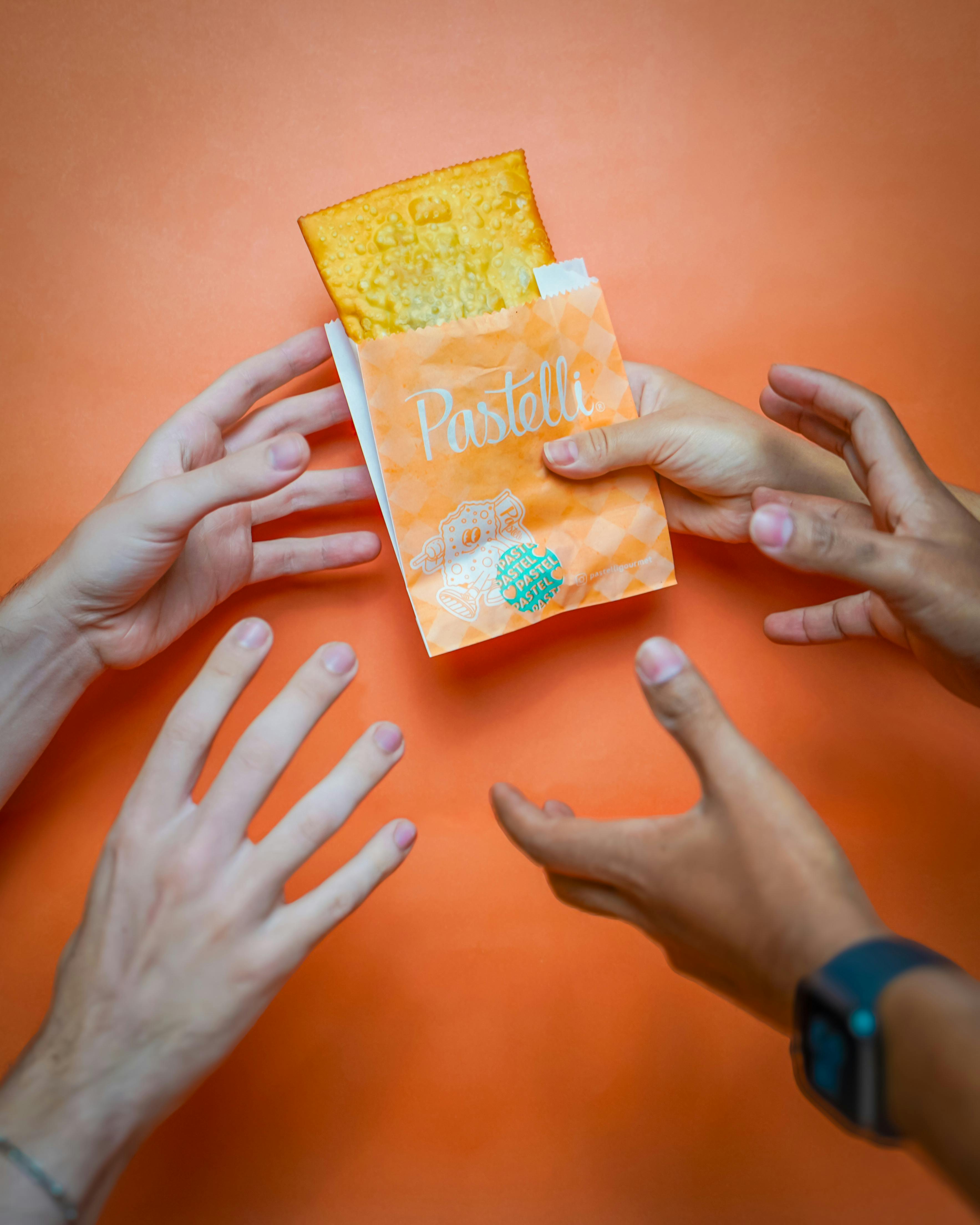 Hands Reaching Towards Hot Pouch Snack · Free Stock Photo