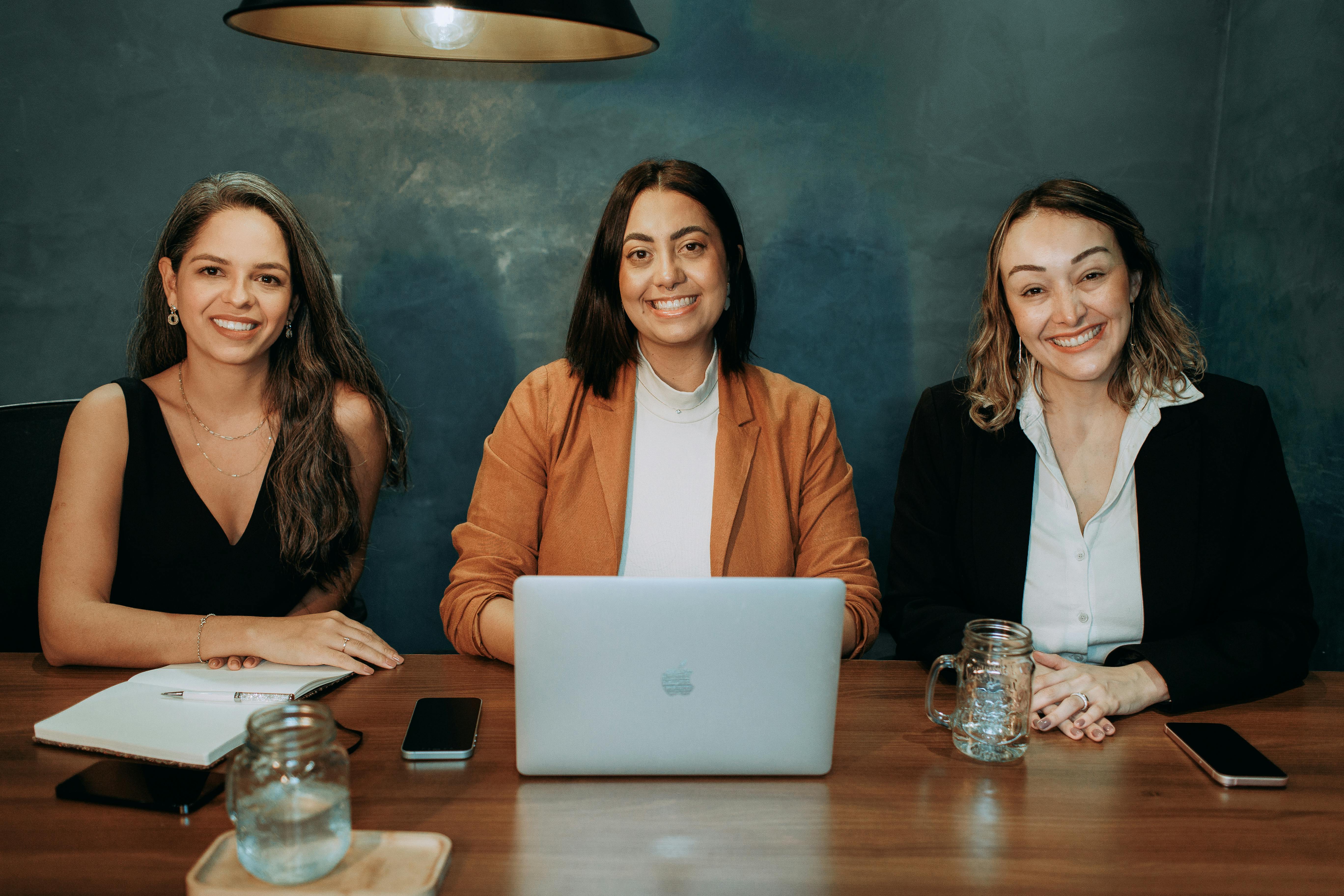 Smiling Women Posing Sitting Together at Table with Laptop · Free Stock ...