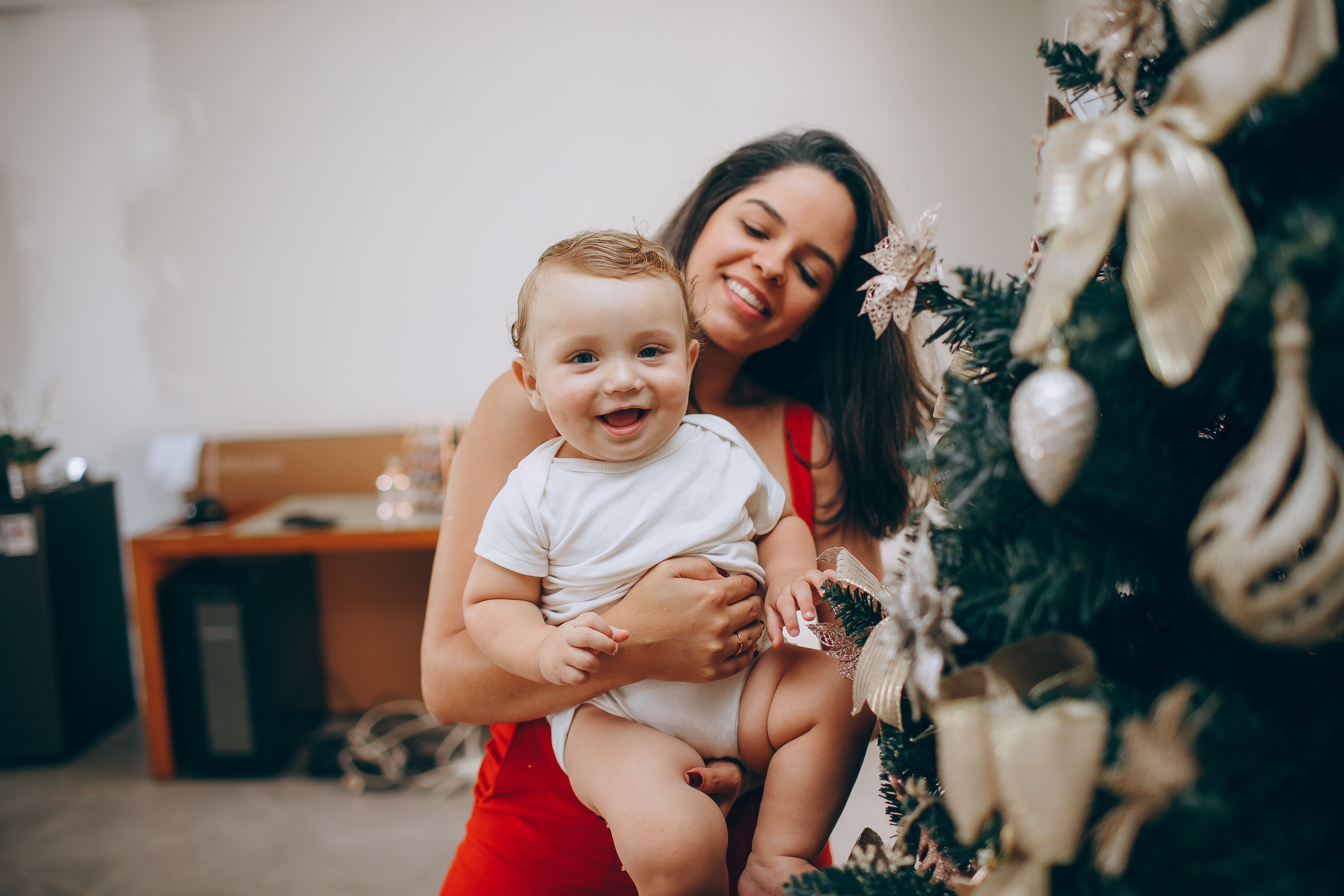Woman Sitting under Christmas Tree Holding Baby · Free Stock Photo