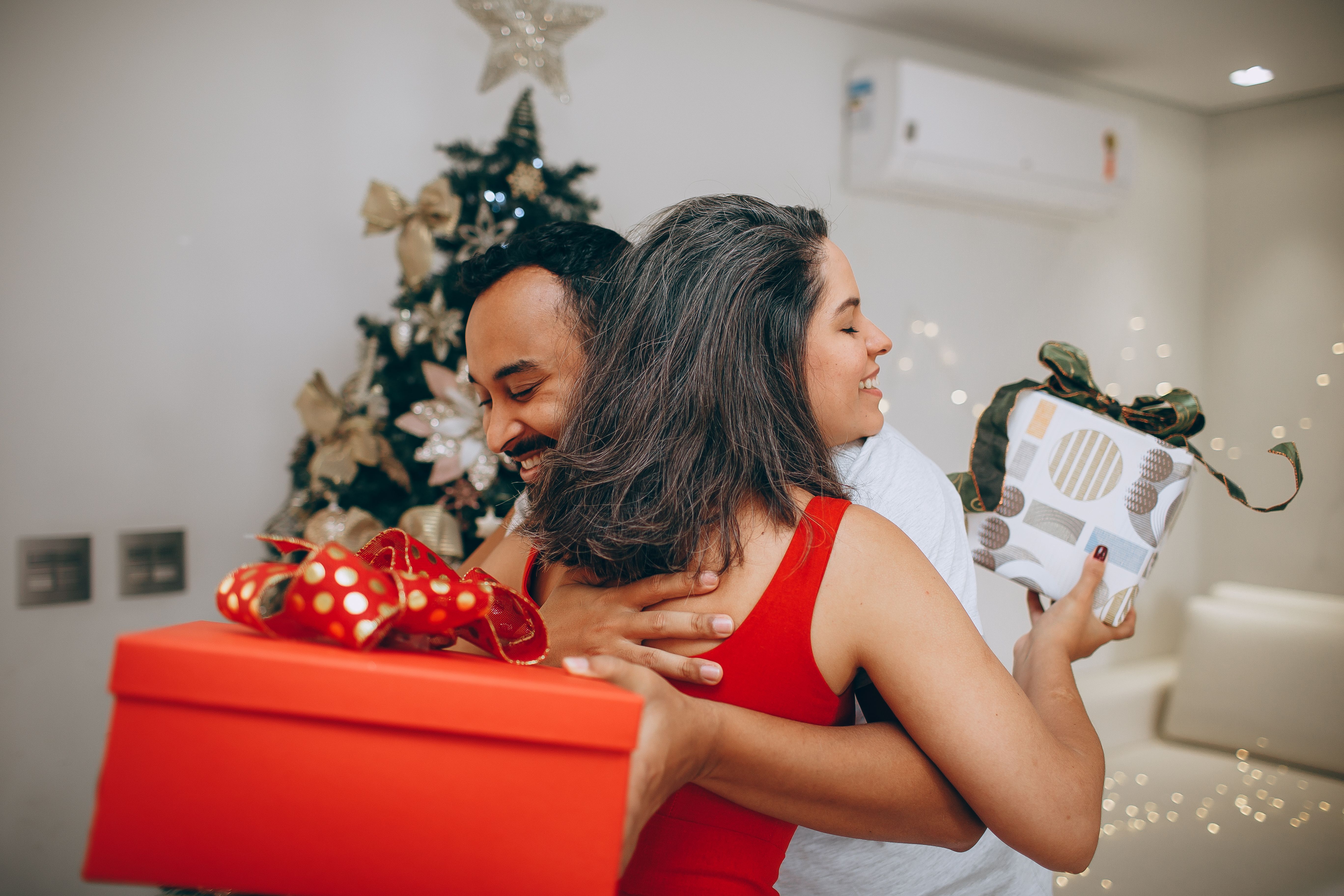 Couple Embracing while Sharing Christmas Presents · Free Stock Photo