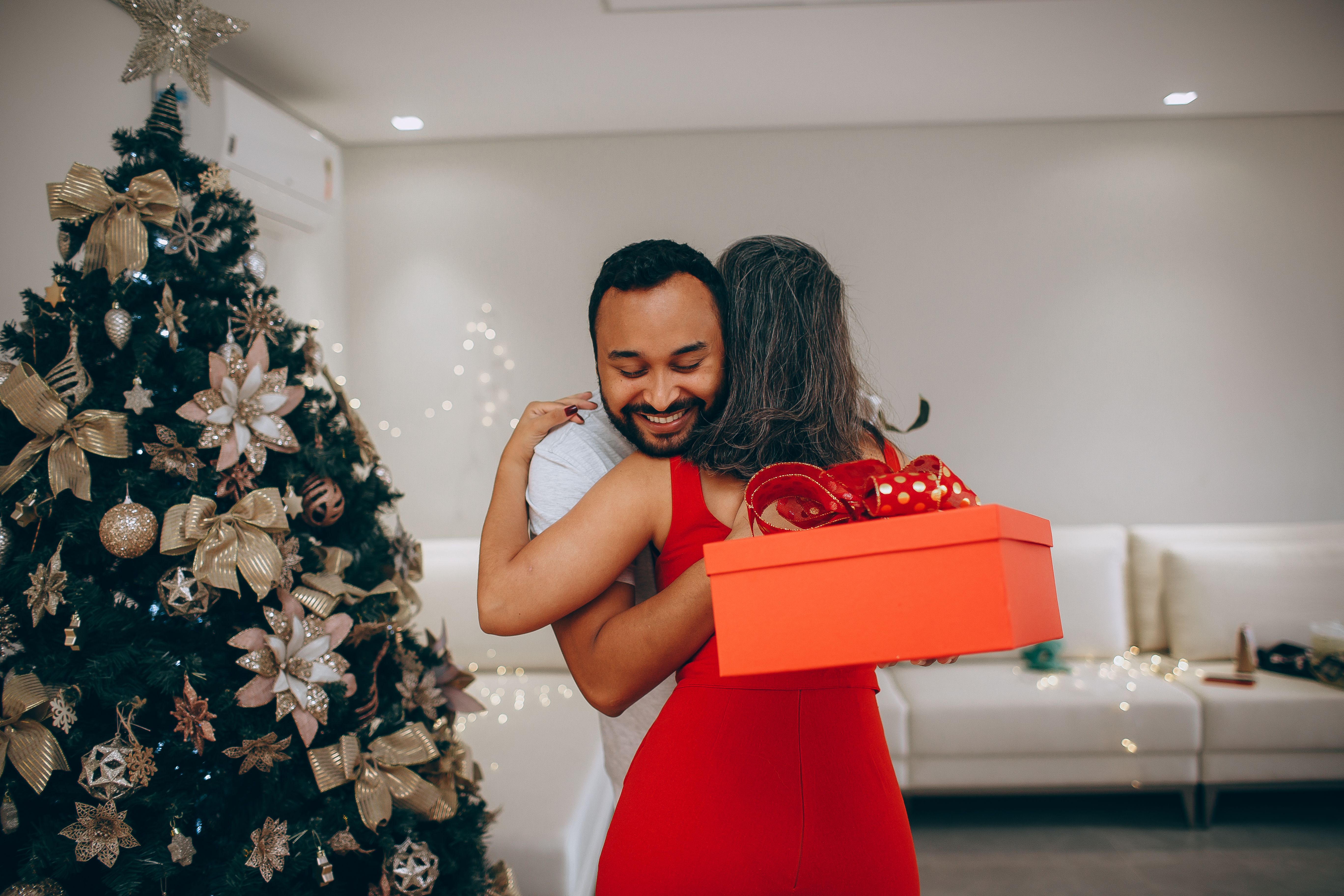 Man Holding Christmas Gift and Hugging Woman in Dress · Free Stock Photo