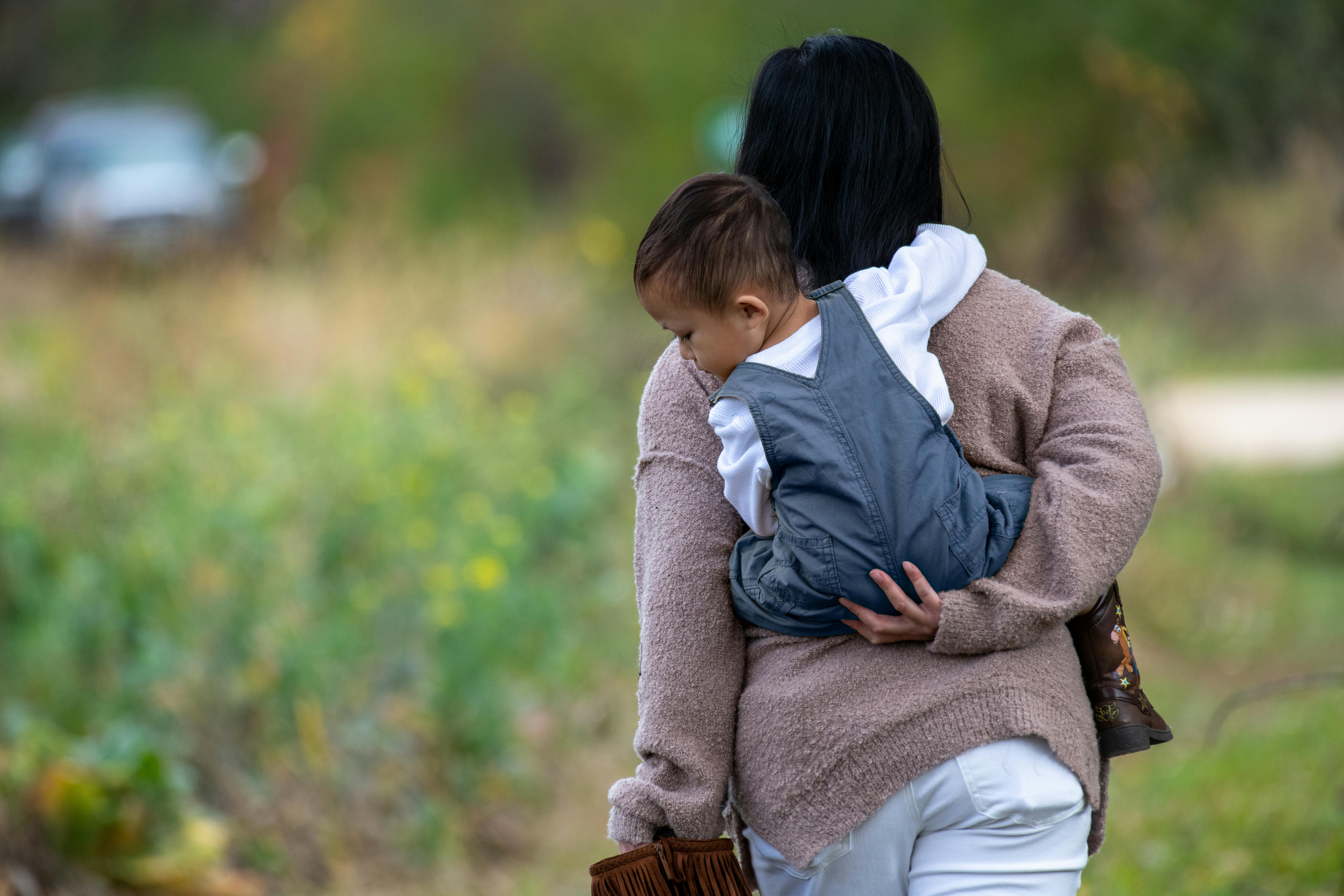 Back View of a Woman Carrying Her Baby on Her Back · Free Stock Photo