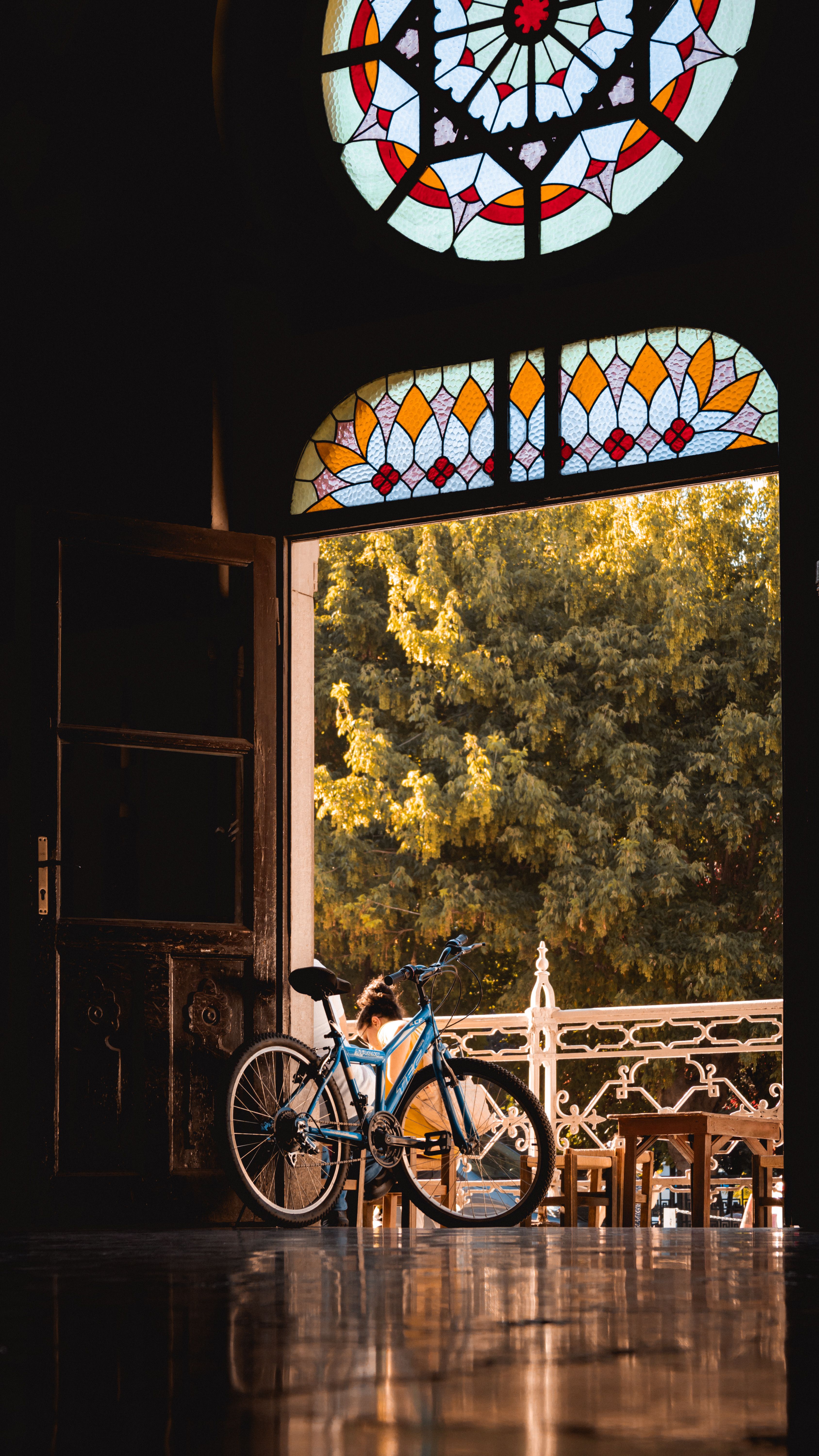 A bicycle is parked in front of a stained glass window · Free Stock Photo