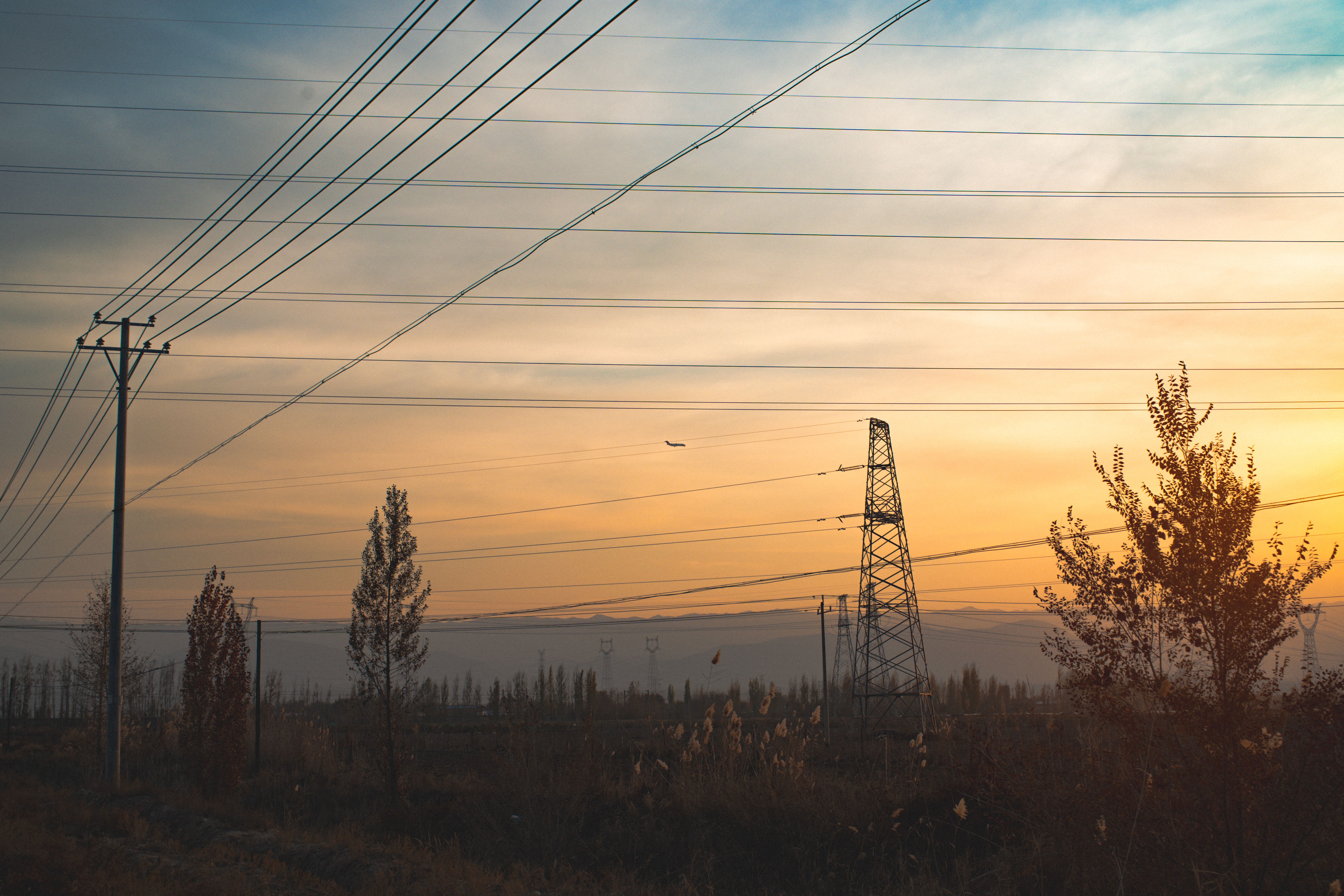Power Line Cables and Towers on Grassland at Sunset · Free Stock Photo