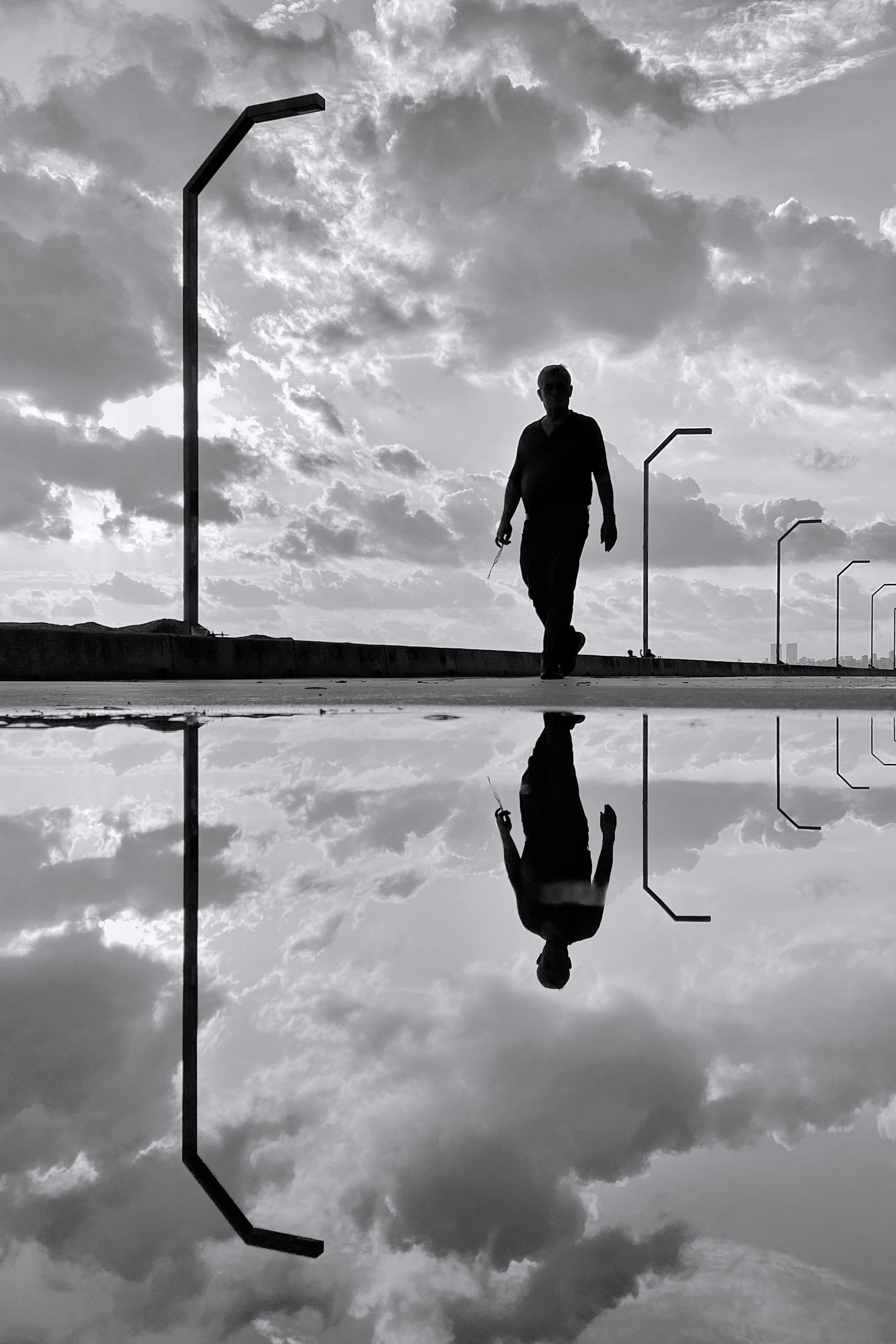 Man Walking near Water Puddle on Road · Free Stock Photo