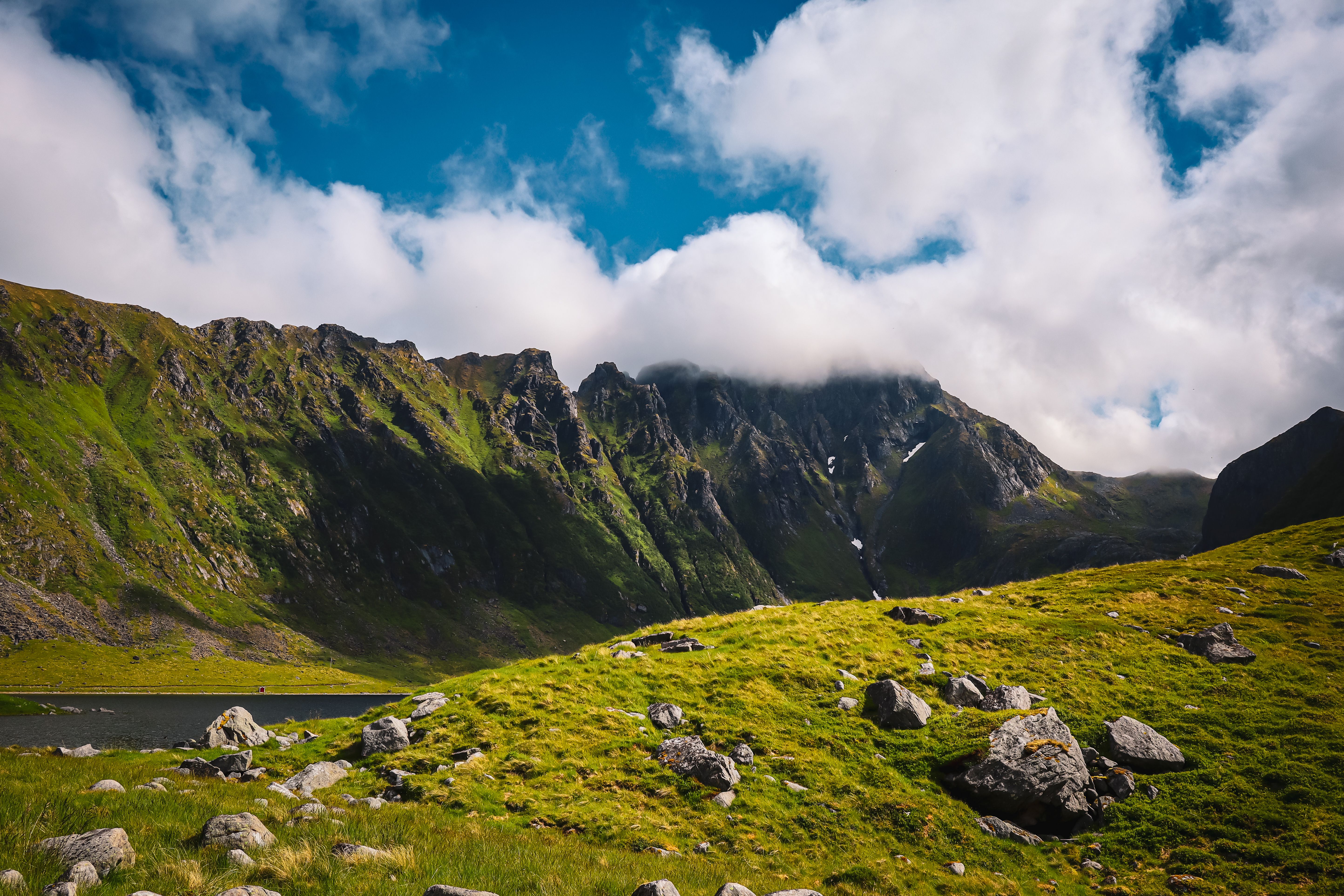 A grassy hill with mountains in the background · Free Stock Photo